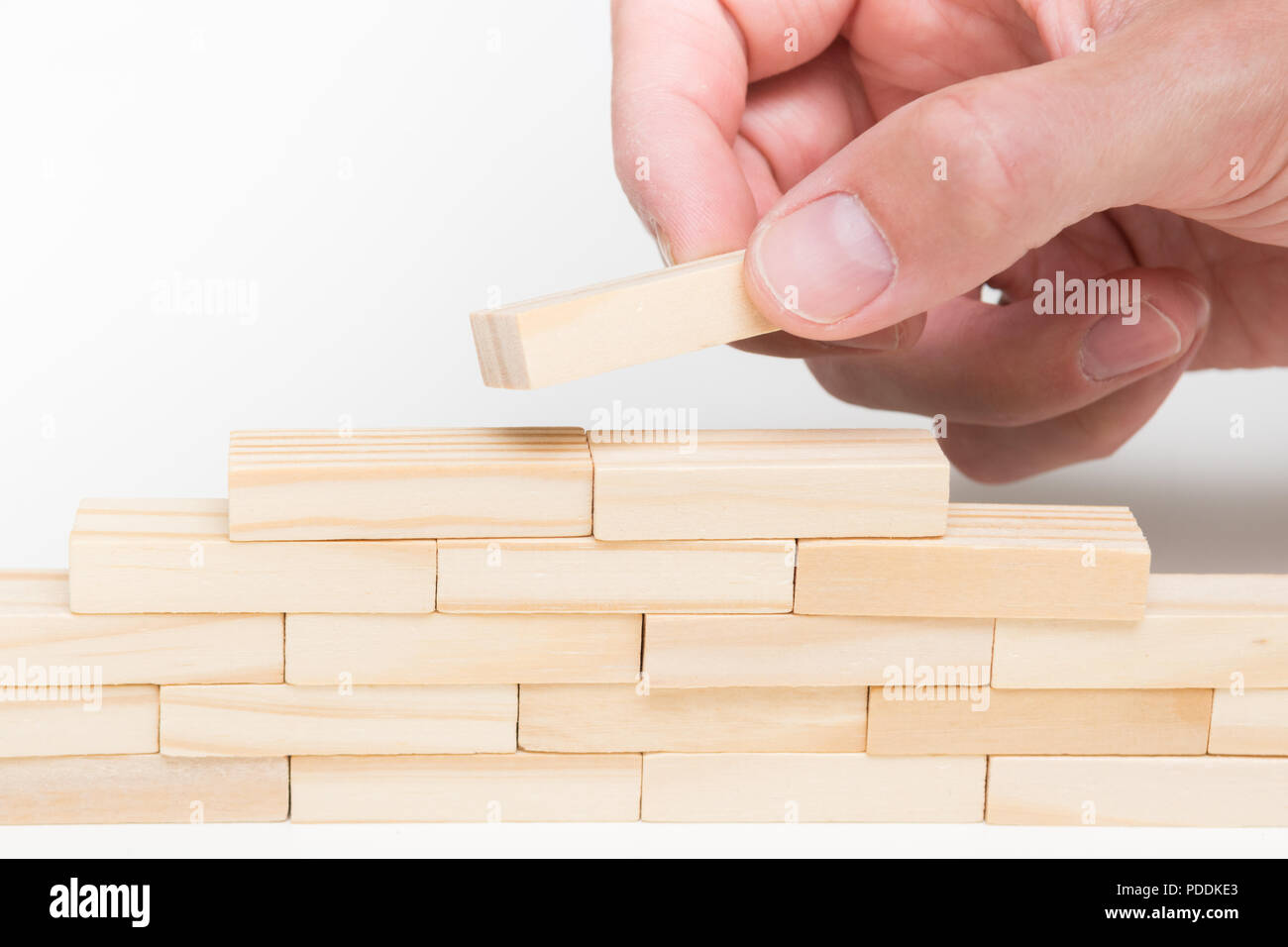 Hand adding final piece to block tower. Business solutions and problem ...