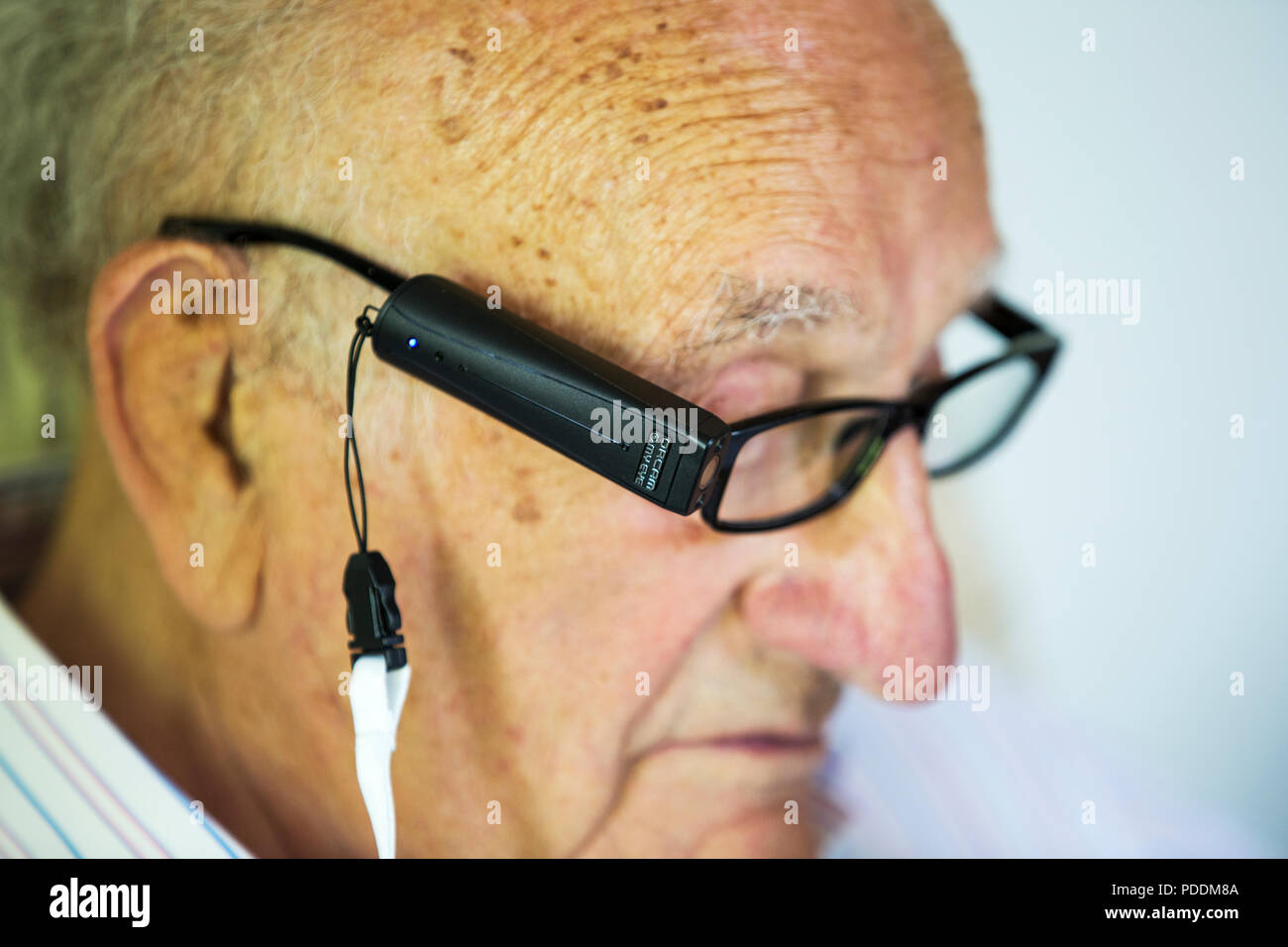 A Pensioner With Macular Degeneration Eyesight Reading Problems Uses An 