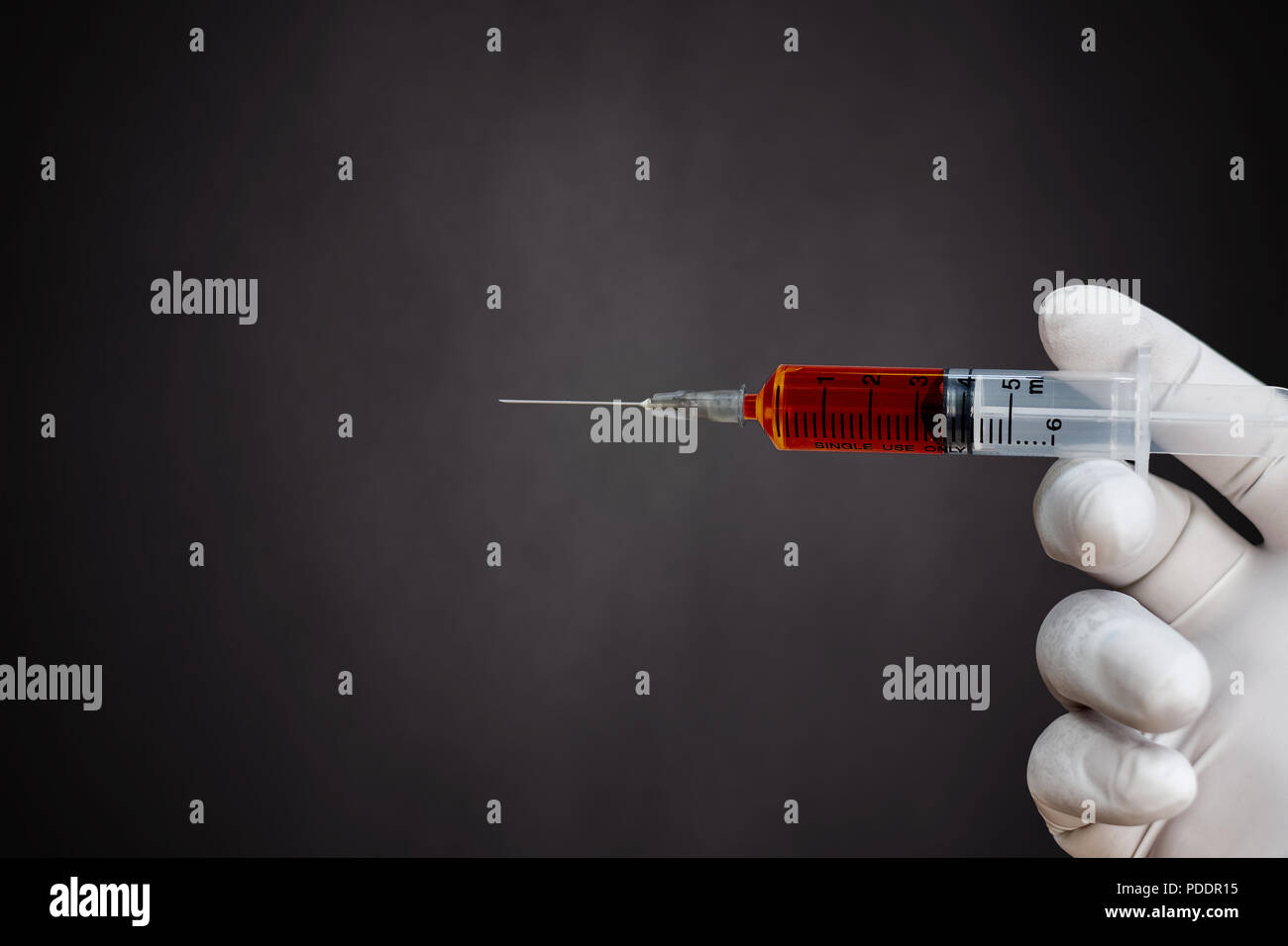 Syringe in a hand in medical gloves, ready for injection with ...