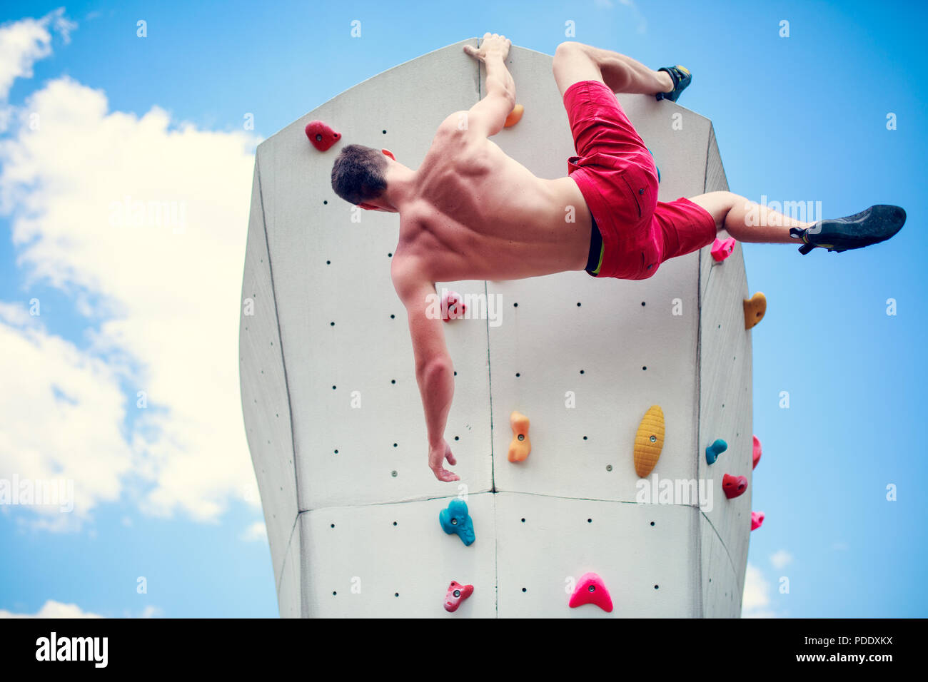 Photo from back of young athletic man exercising on wall for climbing ...