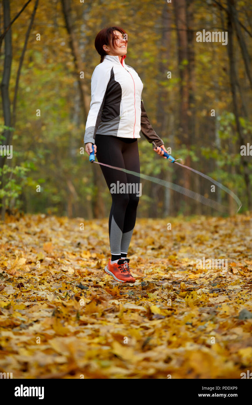 Picture of side view of sports girl jumping rope at autumn forest Stock ...