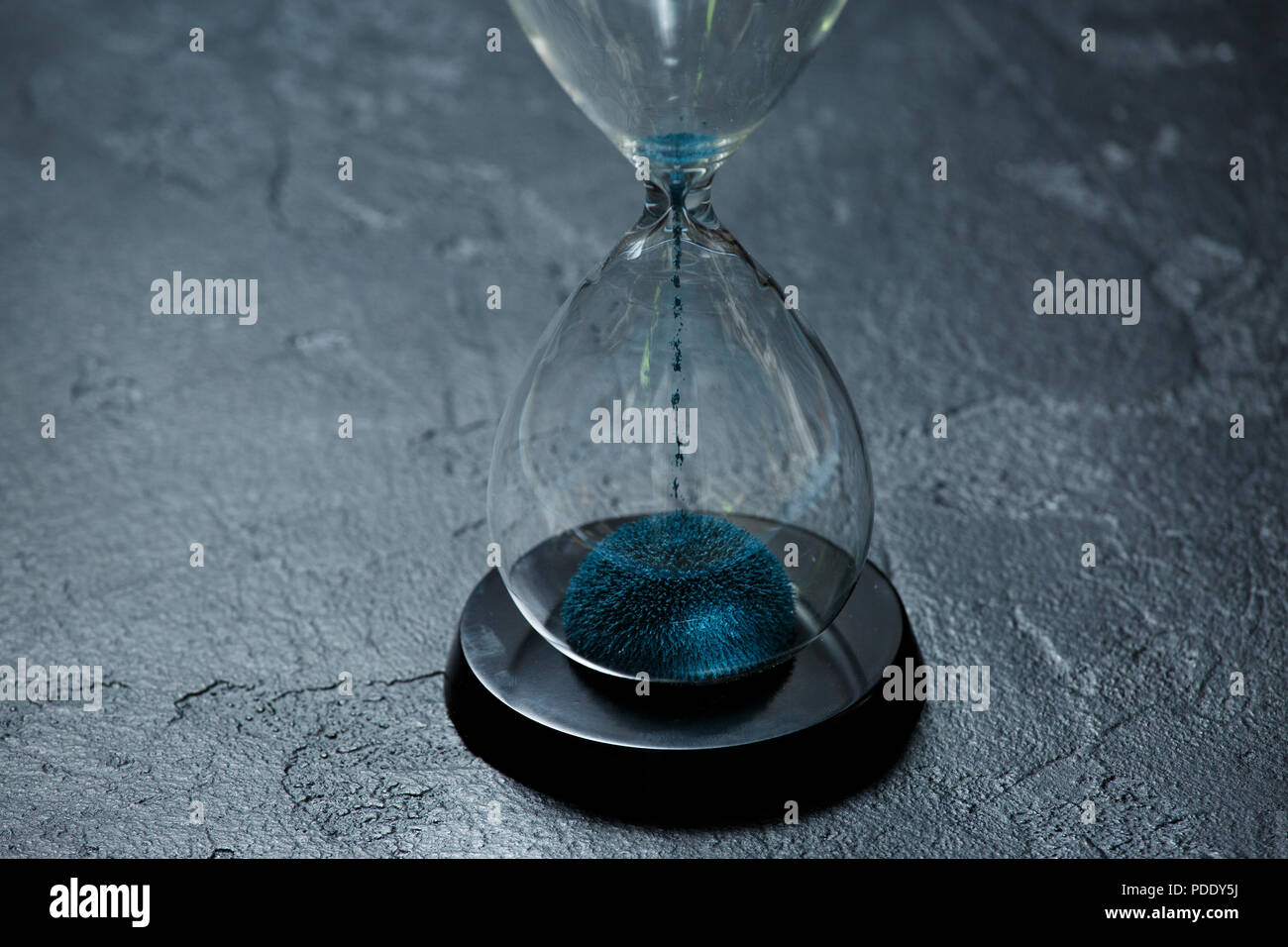 Photo of glass hourglass with blue sand on black stone background Stock ...