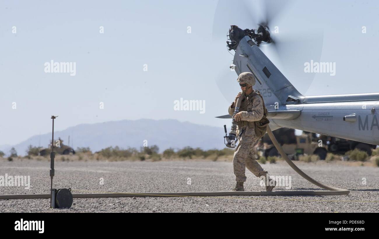 U.S. Marine Corps Cpl. Toby J. Hash carries a fuel hose away from an AH ...