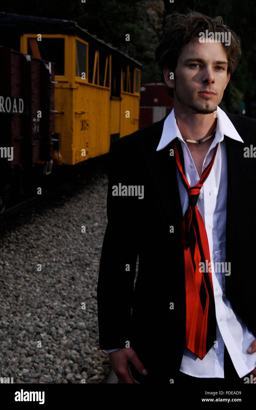 Disheveled man in a suit near an old narrow guage coal burning train ...
