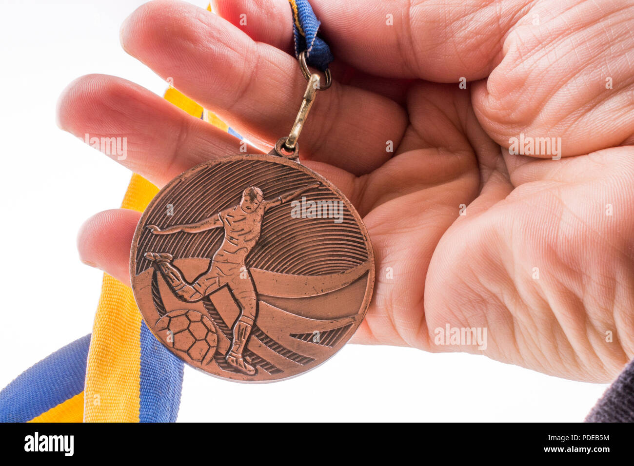 Hand holding a medal with blue and yellow ribbon Stock Photo - Alamy