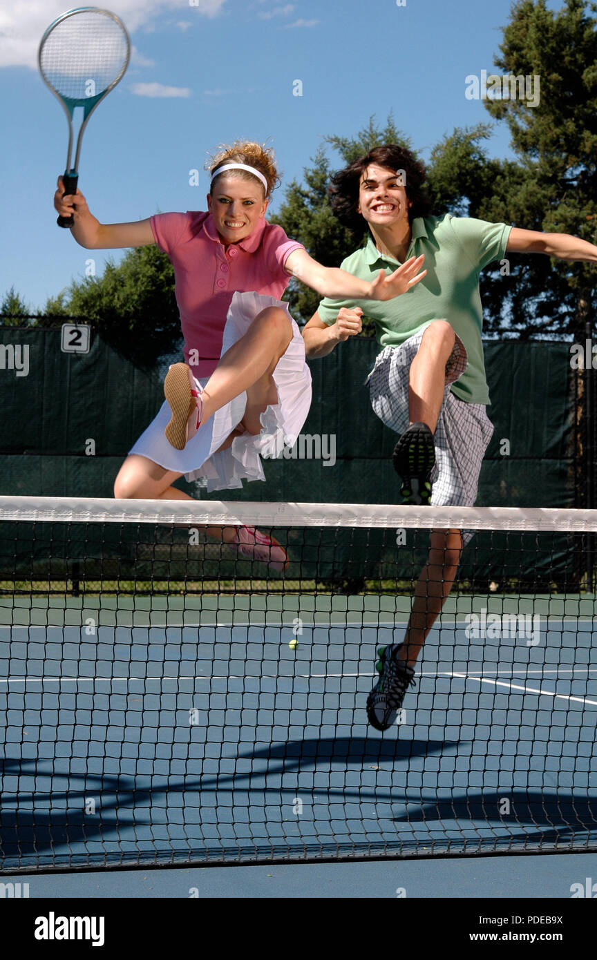 A young couple jumps over the net with tennis rackets Stock Photo - Alamy