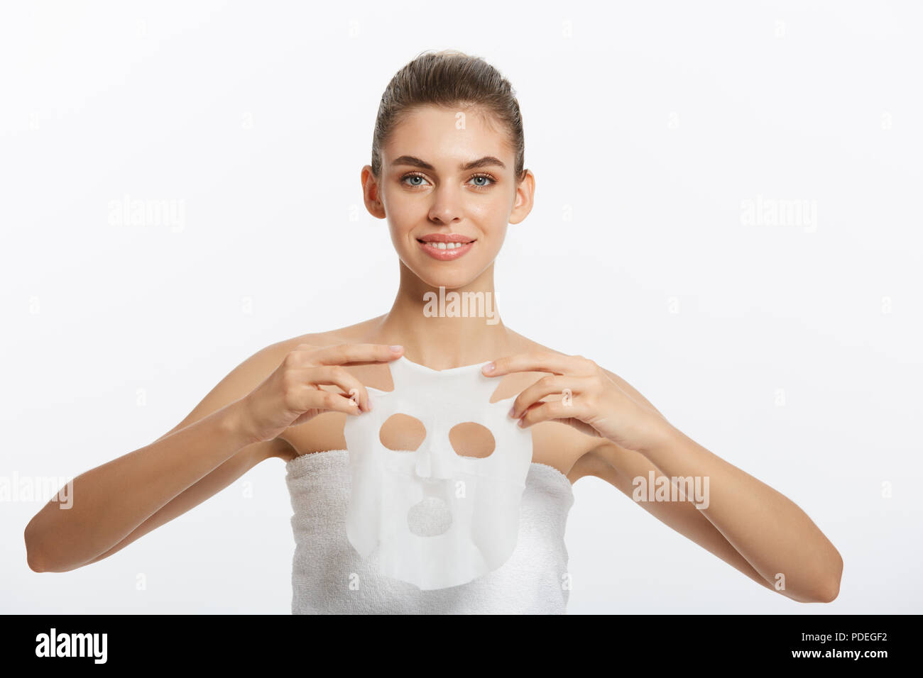 Young girl with facial mask looking at camera over white background ...