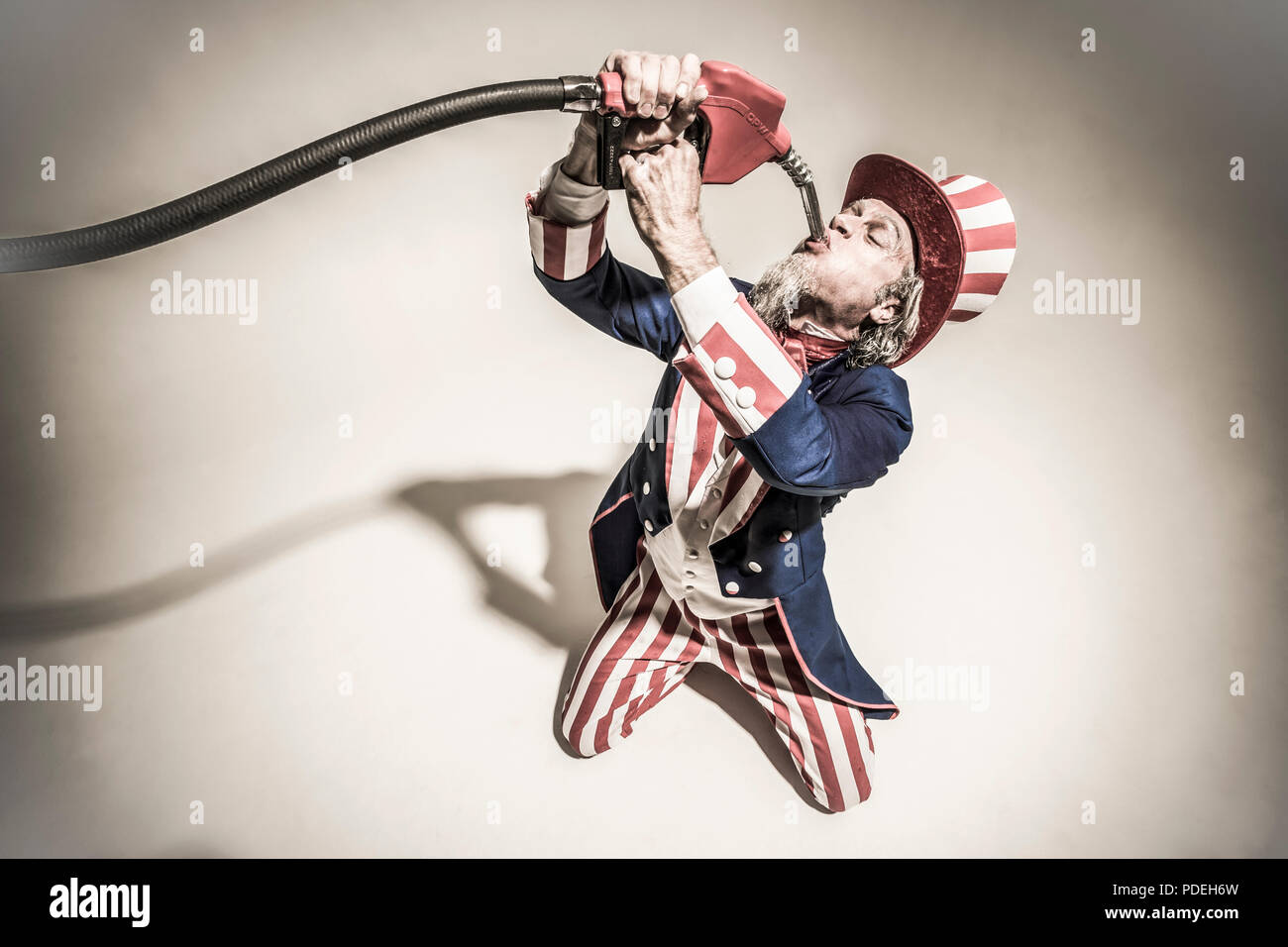 Uncle Sam sucking gasoline from a gas pump nozzle. Addicted to oil / fossil fuels Stock Photo ...