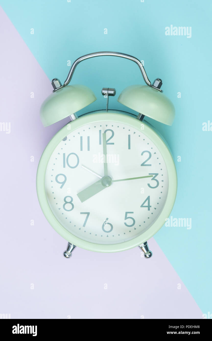 Flat lay vintage alarm clock on sweet pastel colored paper top view ...