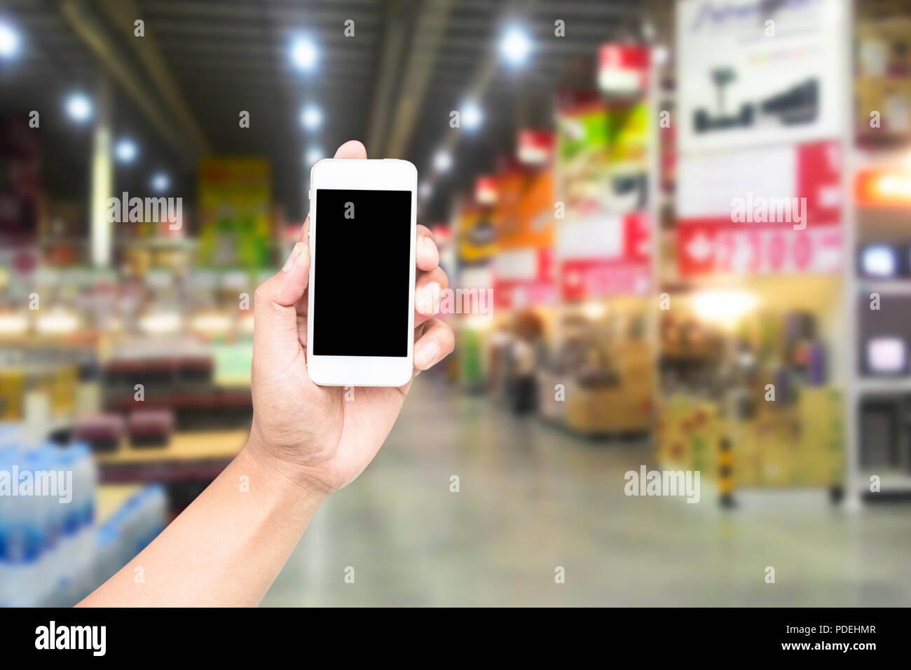 Male hand holding mobile smart phone on Supermarket blur background ...