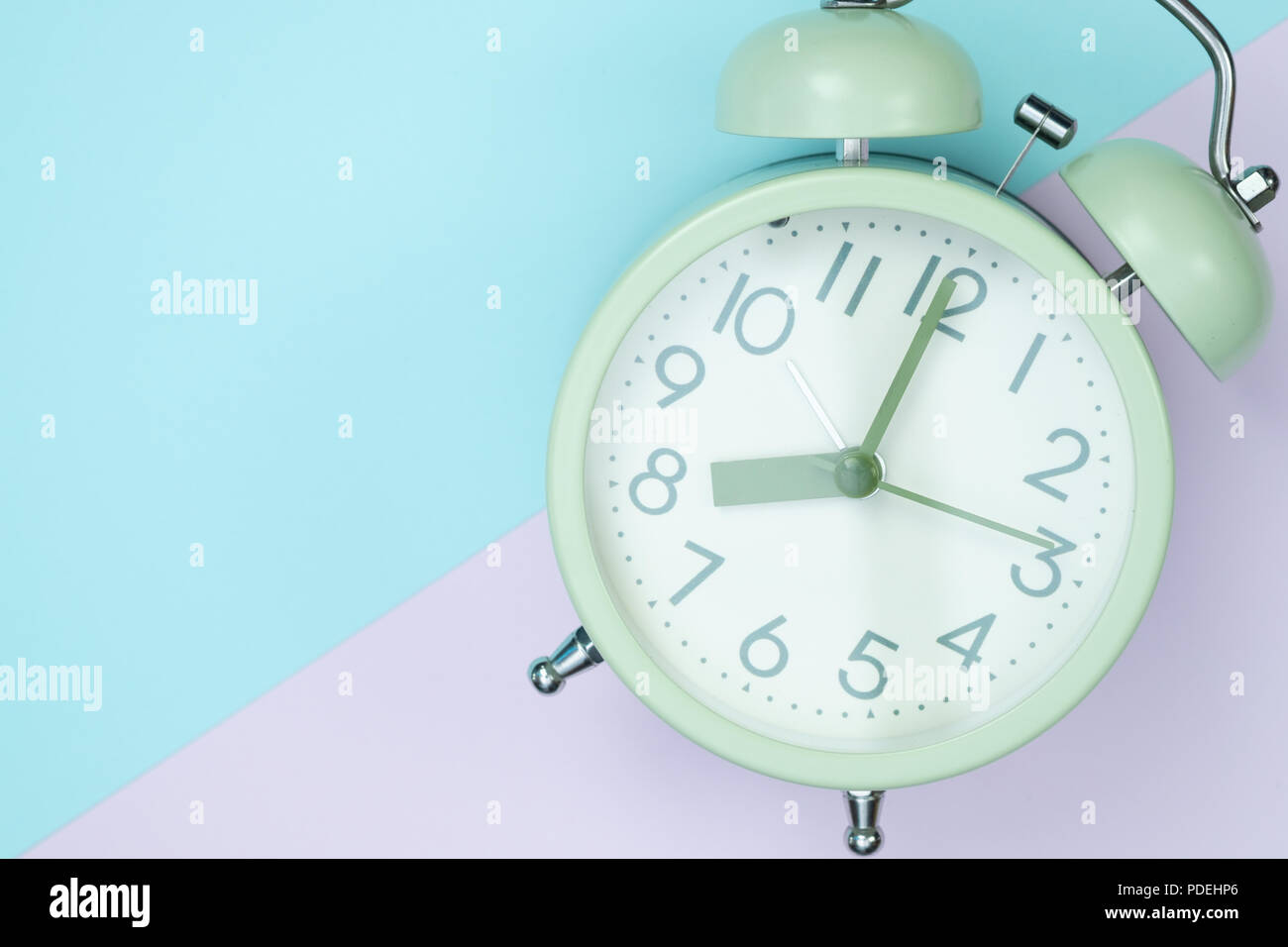 Flat lay vintage alarm clock on sweet pastel colored paper top view ...