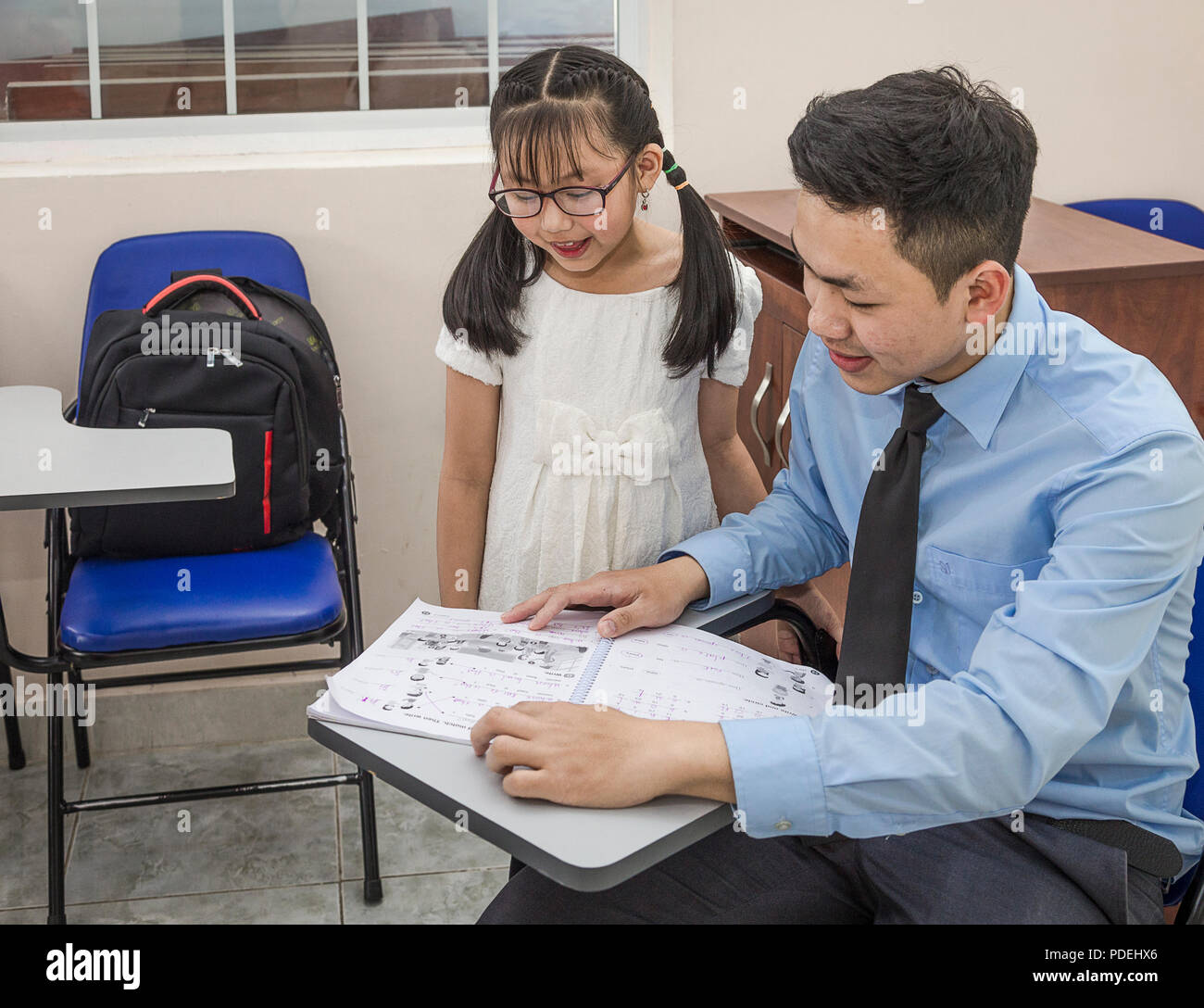 Asian student gets is happy after passing test as male teacher goes ...