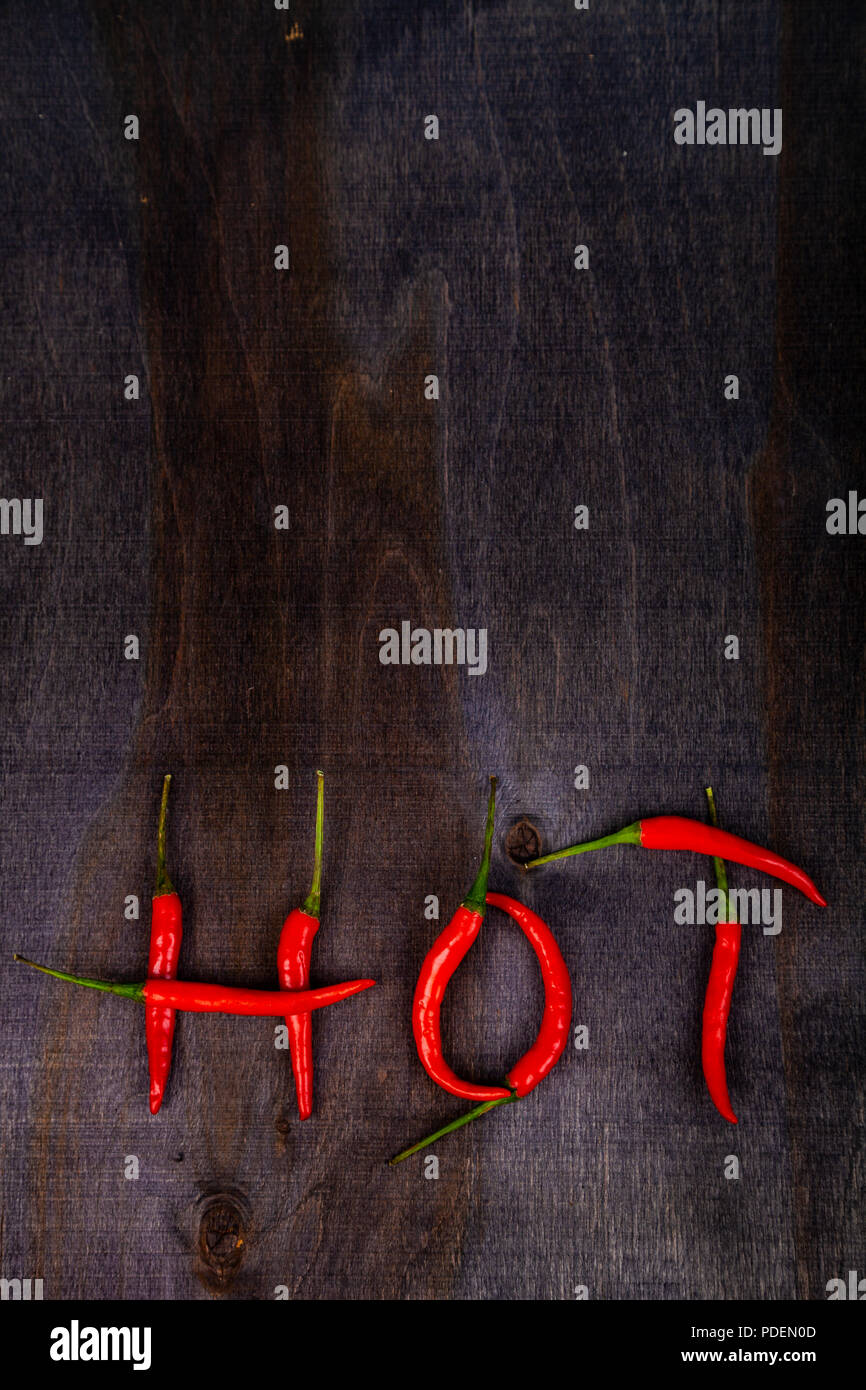 Red chilli pepper is a dark background. Word "hot" is made from chili ...