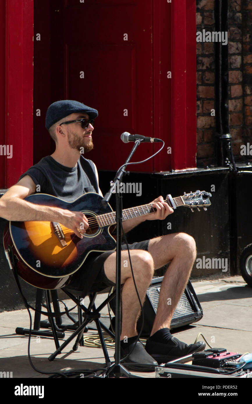City Busker playing acoustic guitar on a side-walk in York, North ...