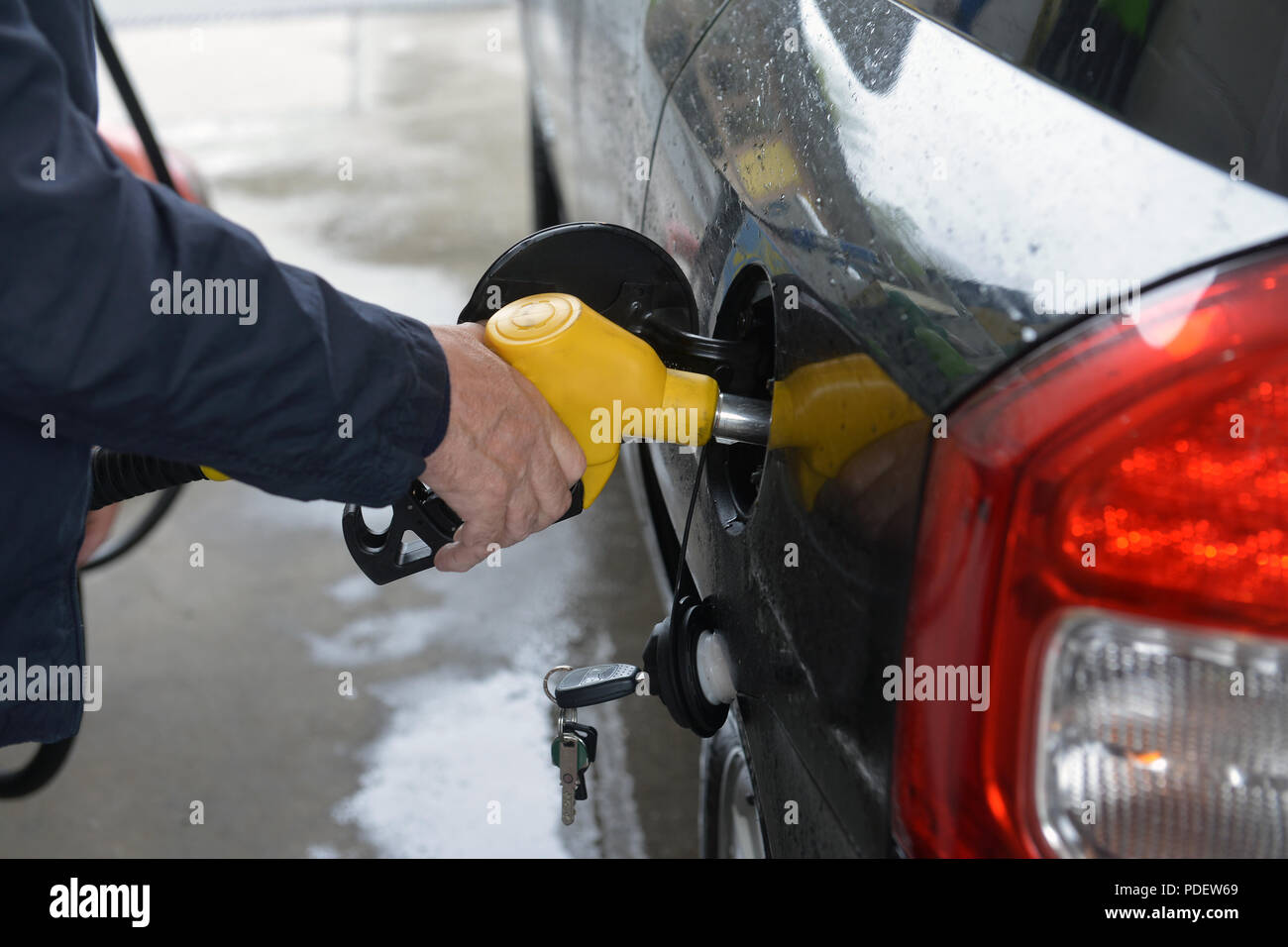 man hand refilling up gas tank of the car with green eco fuel on a ...