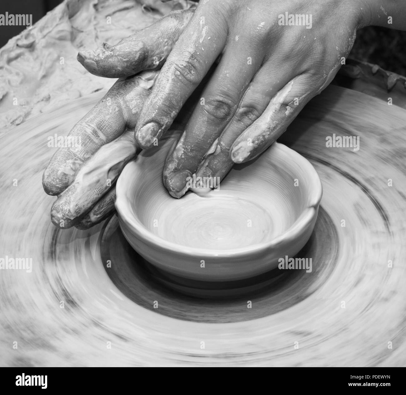 Woman hands in clay at process of making clay bowl on pottery wheel ...