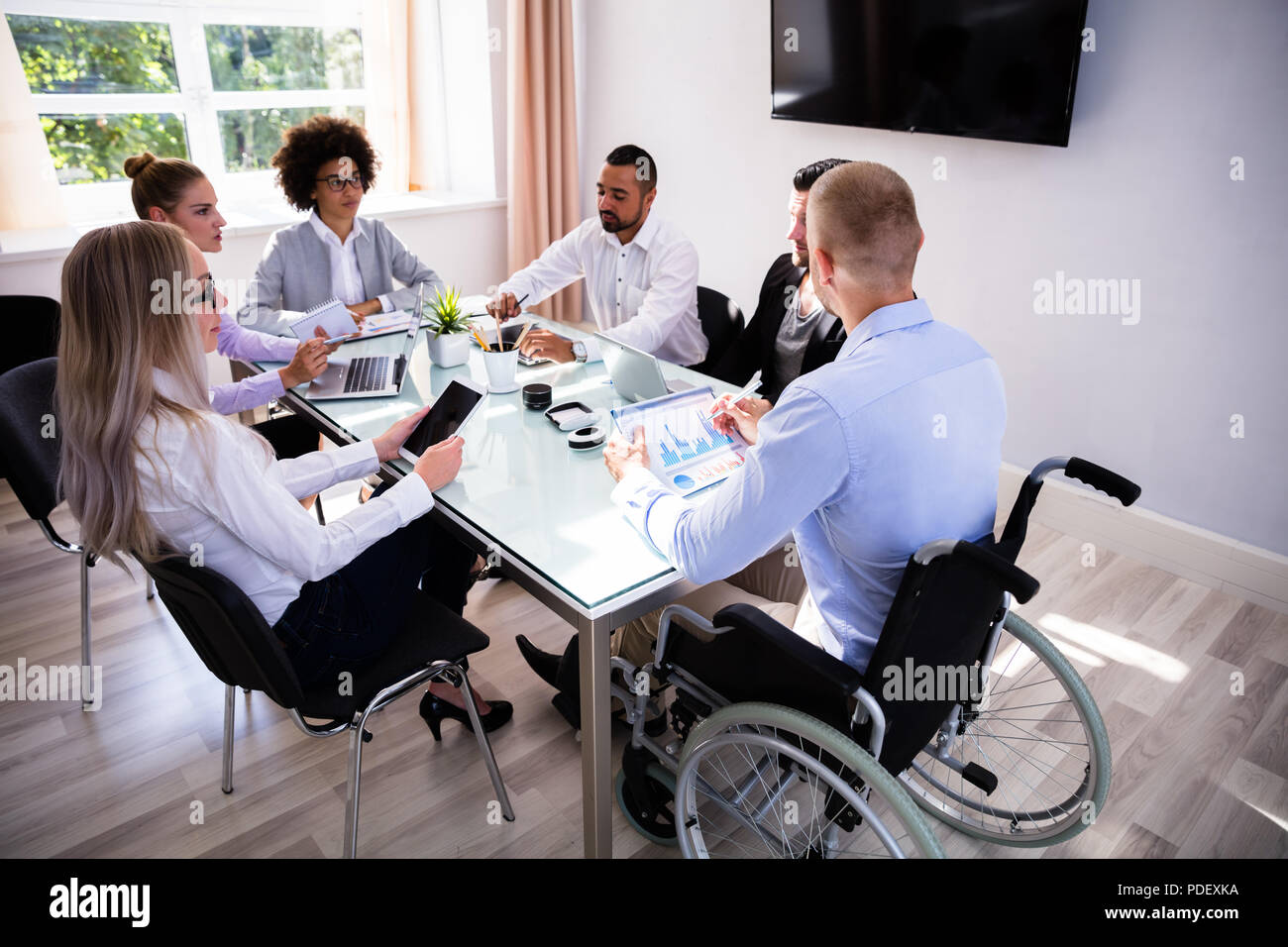 Disabled Male Manager Sitting With His Colleagues At Workplace Stock ...
