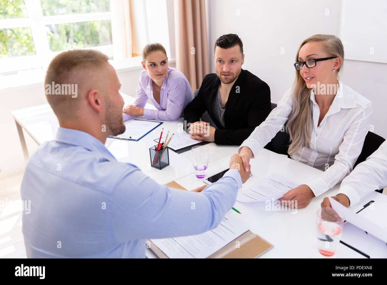 Smiling Young Man Shaking Hands With Female At Interview Stock Photo ...
