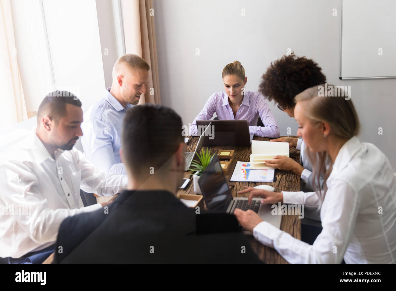 Group Of Businesspeople Sitting In Office During Business Meeting Stock ...
