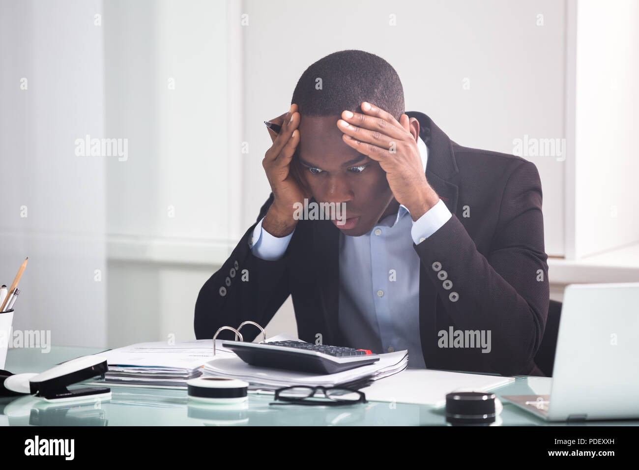 Close-up Of Worried Young Businessman Looking At Calculator On The ...