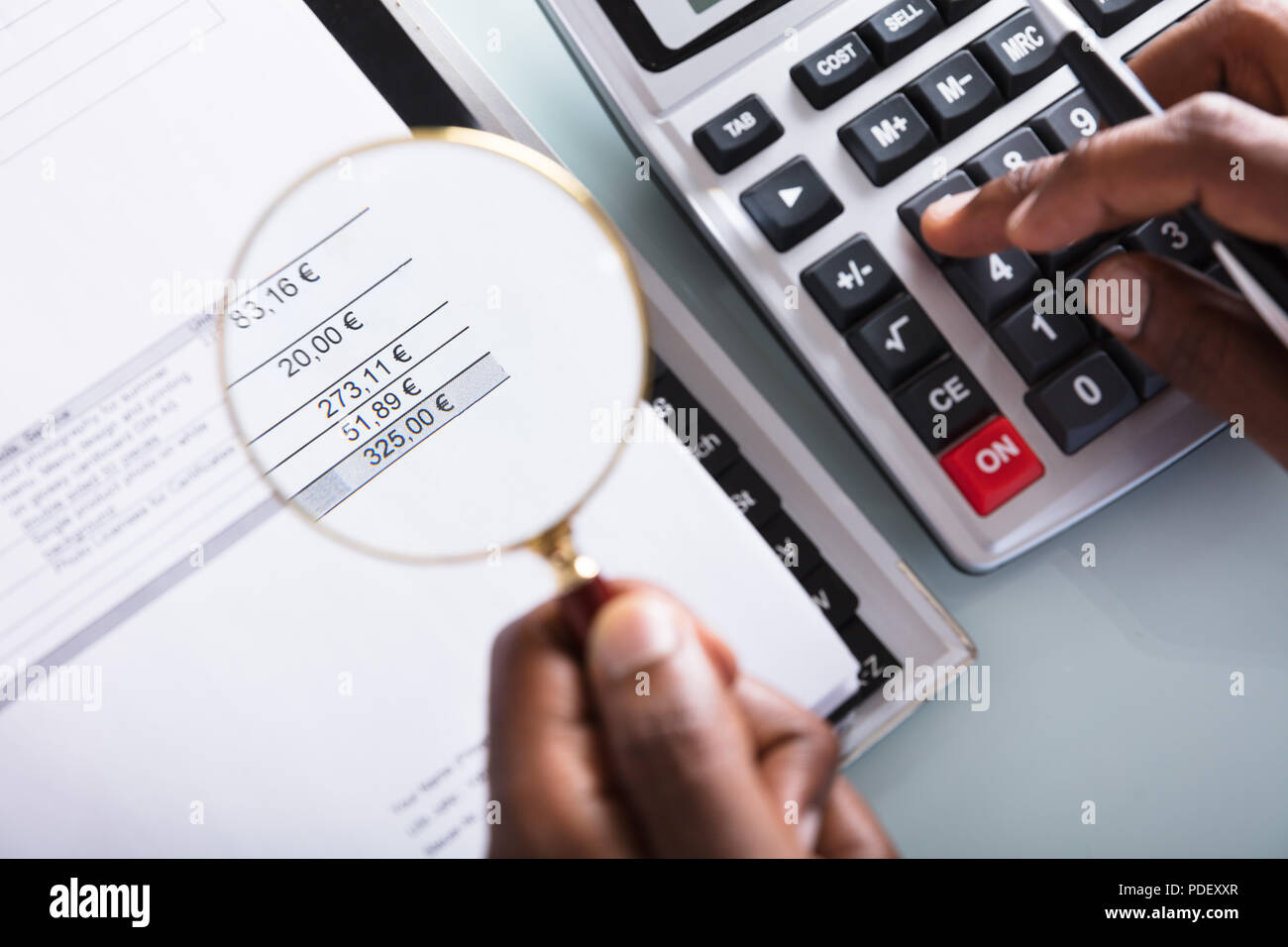 Close-up Of A Businessman Holding Magnifying Glass Over Invoice Using ...