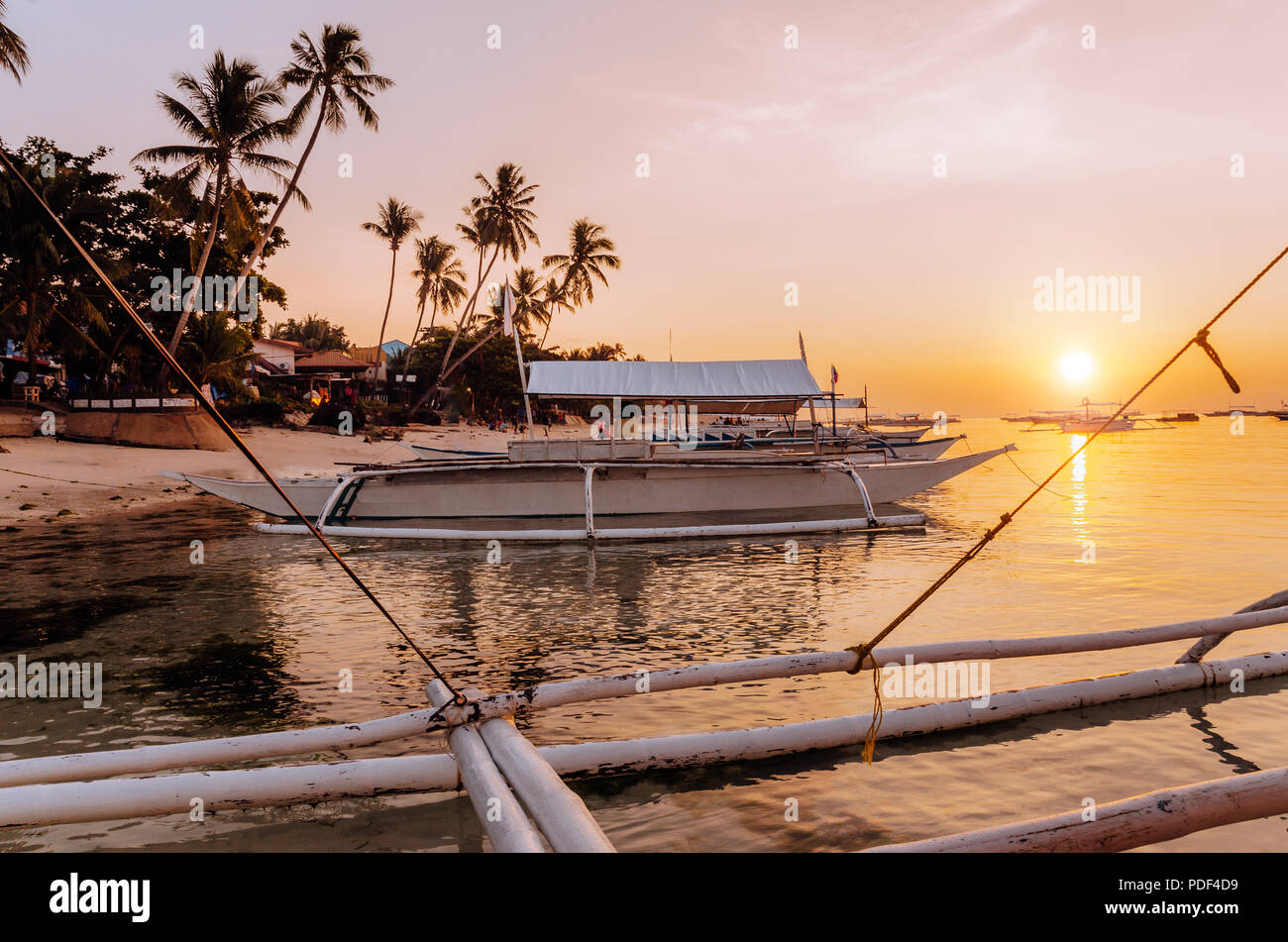 Sunset on the beach with silhouette of banca boat at Panglao Island ...