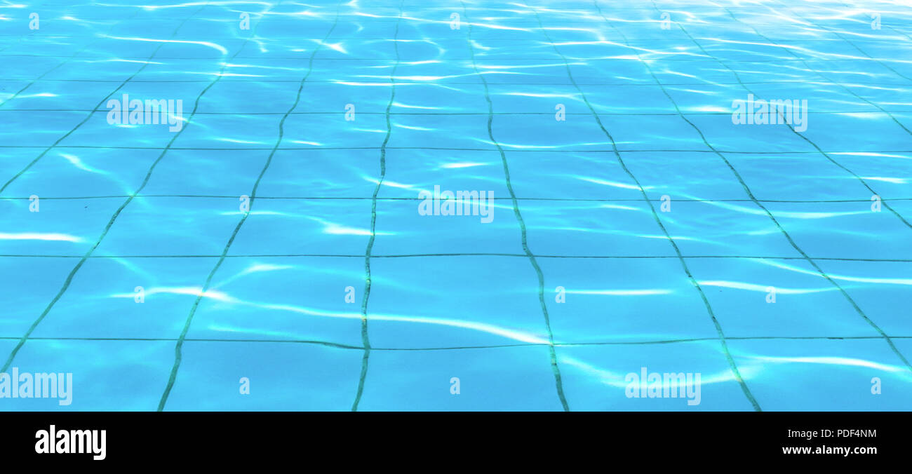 Sun reflection on the clear water ripples of swimming pool with tiles ...