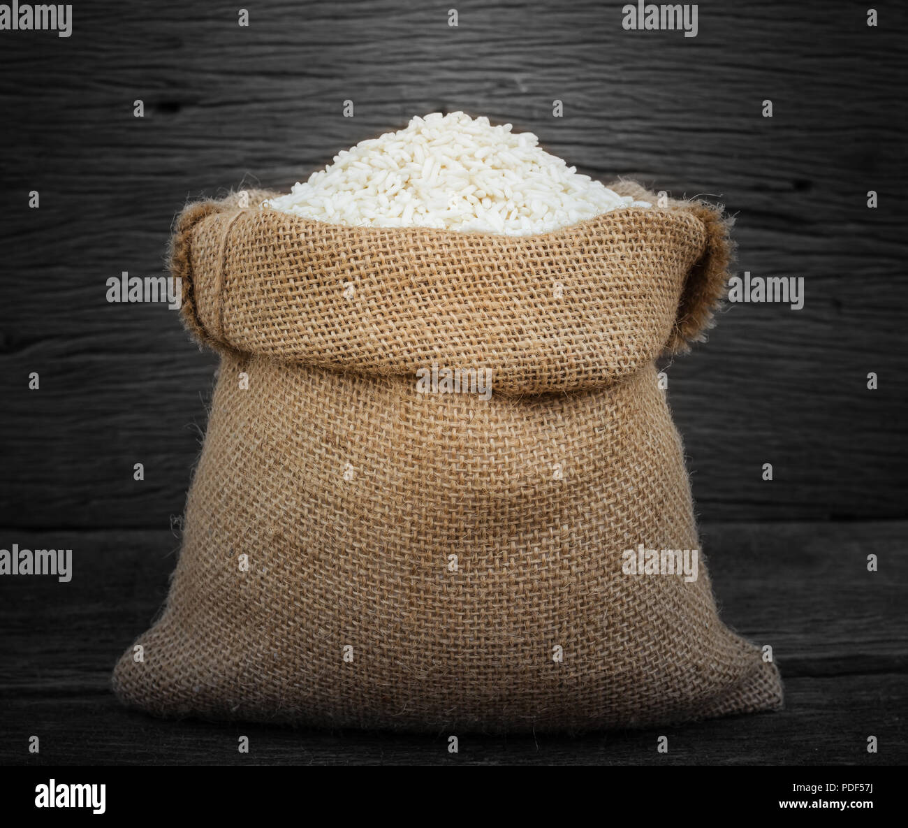 rice in burlap sack on wooden background Stock Photo - Alamy