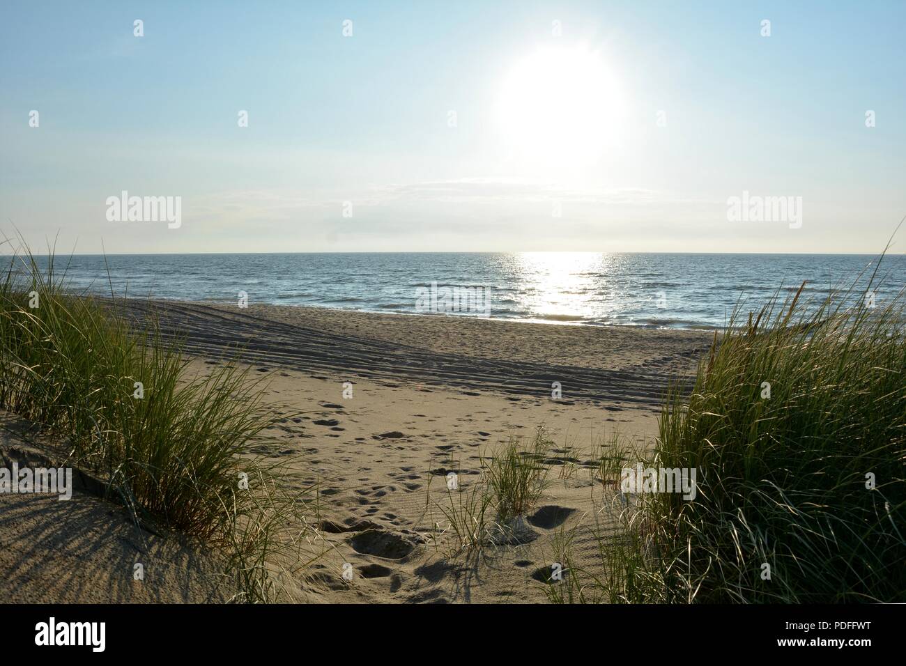 Beach with sun, marsh grass and wooden stages on the North Sea at ...
