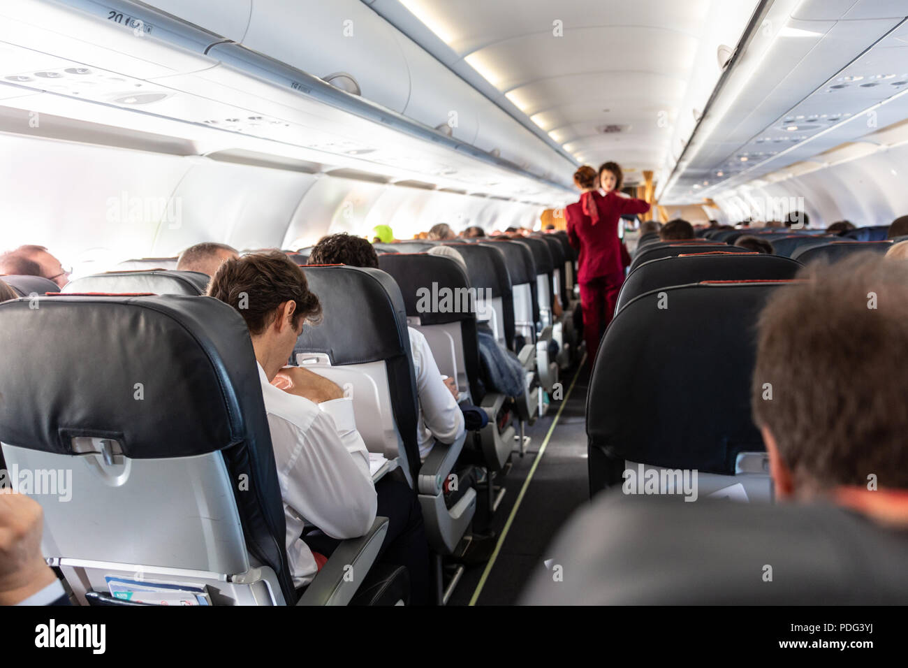 Interior of commercial airplane with passengers on their seats during ...