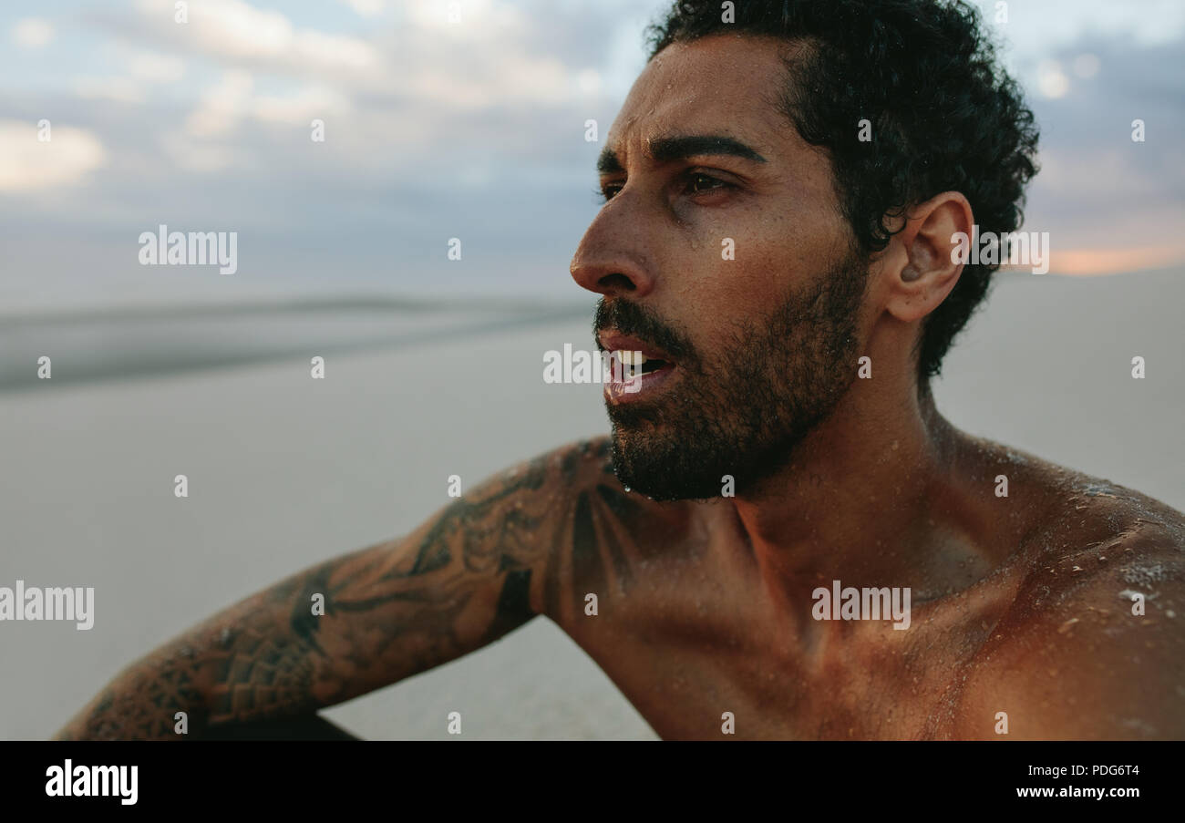 Close up of young man taking rest after exercising in desert. Male ...