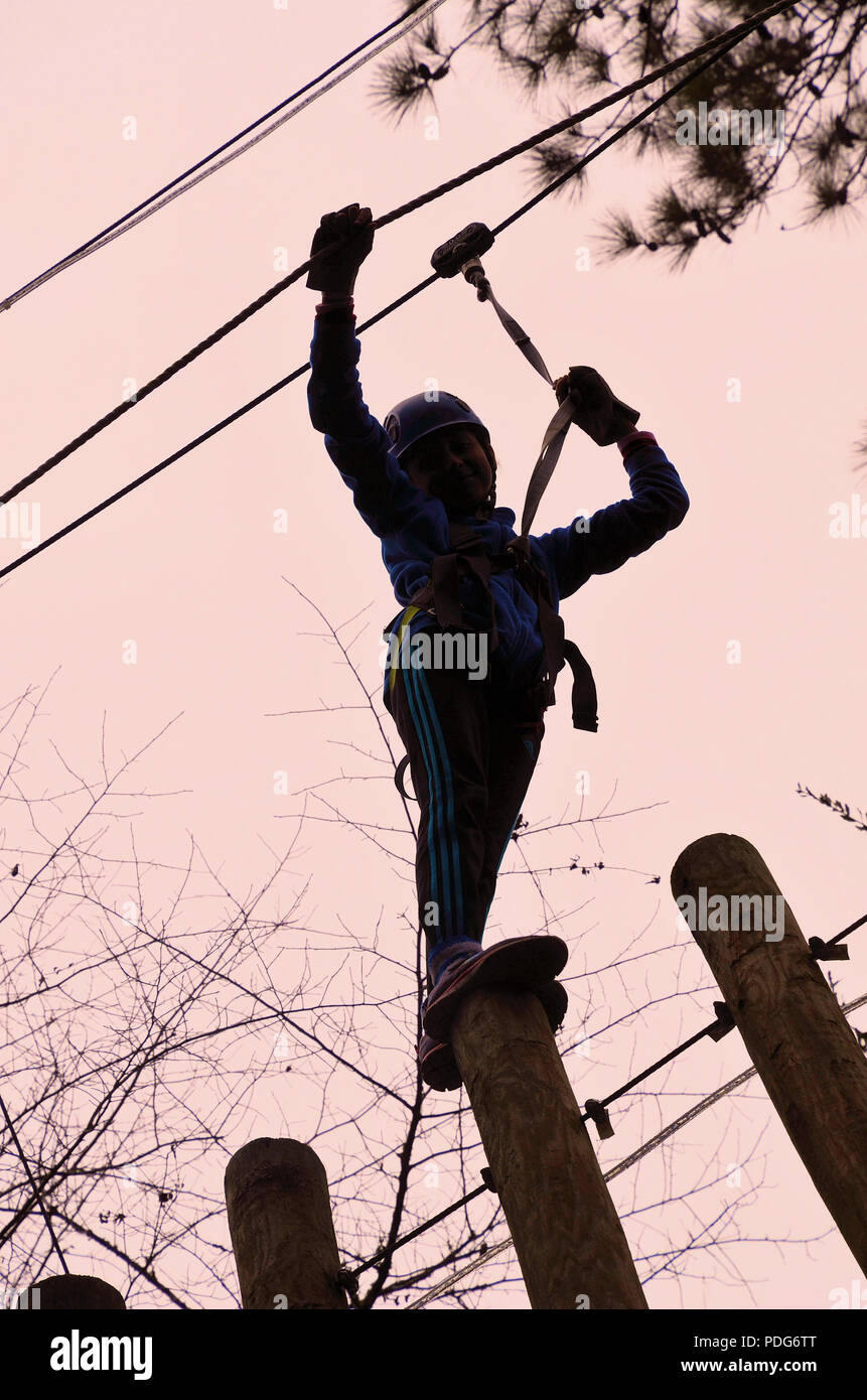 Teenager seen from the ground on the Aerial Adventure Zip Line Park at ...