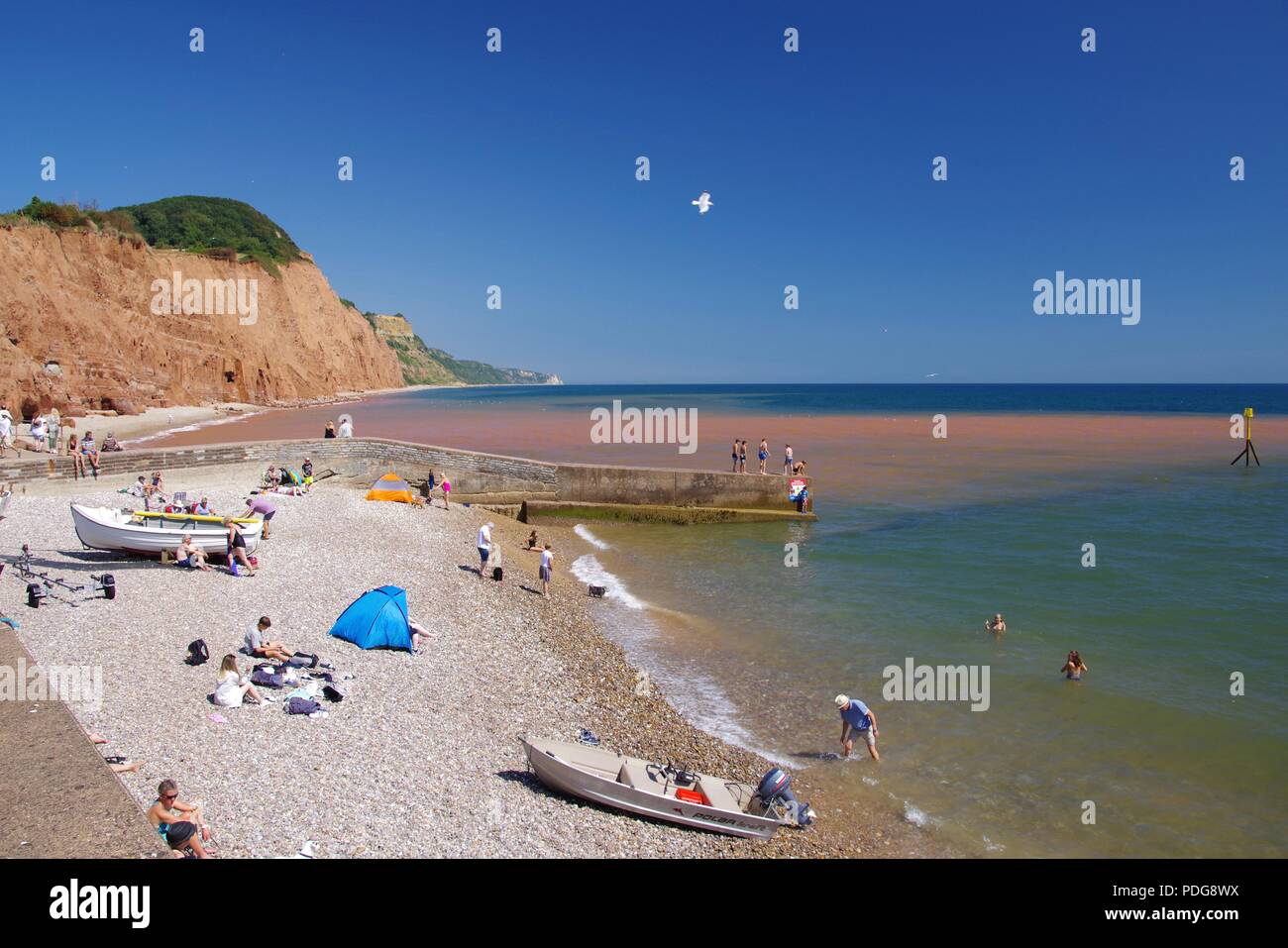 Red Sandstone Cliff beyond a Pebble Beach with Day Trippers. Glorious ...