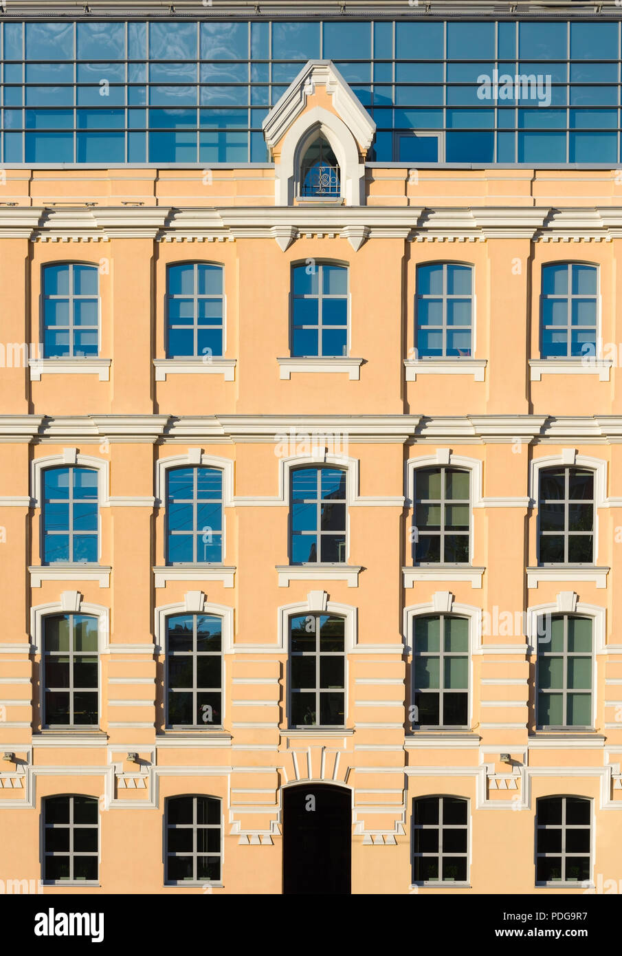 The facade of the yellow building with glass Windows and an attic floor ...