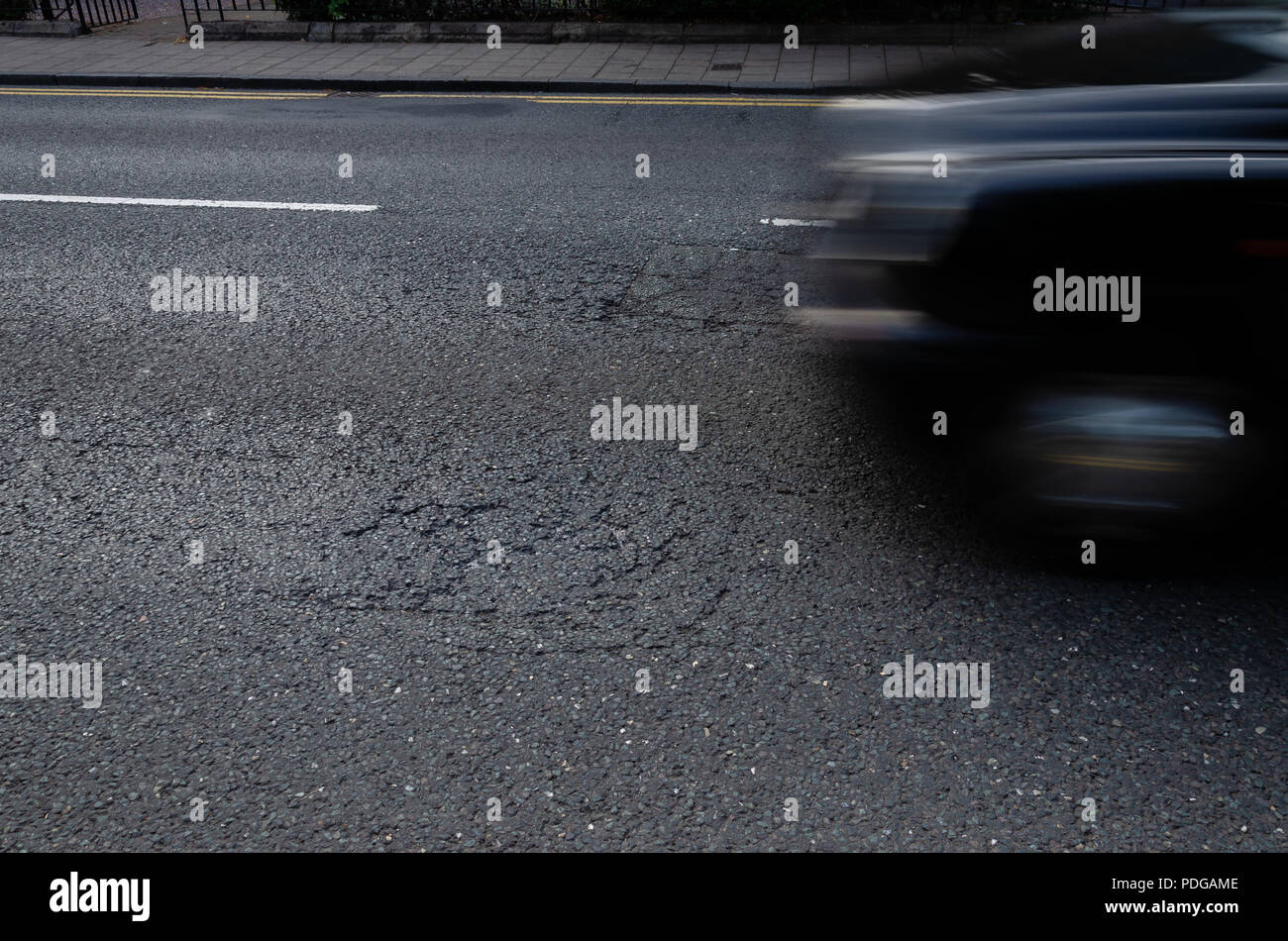 A view of a damaged and worn road surface with an unrecognisable ...