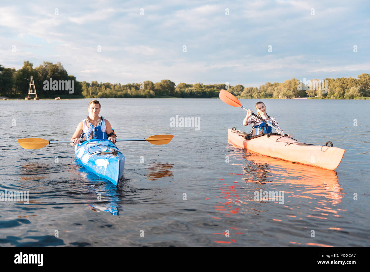 Blonde-haired wife wearing striped shirt kayaking with her sportsman ...
