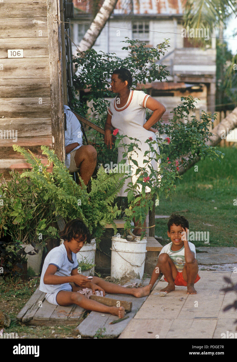 Belizean man sitting in doorway of wooden clad house with children ...