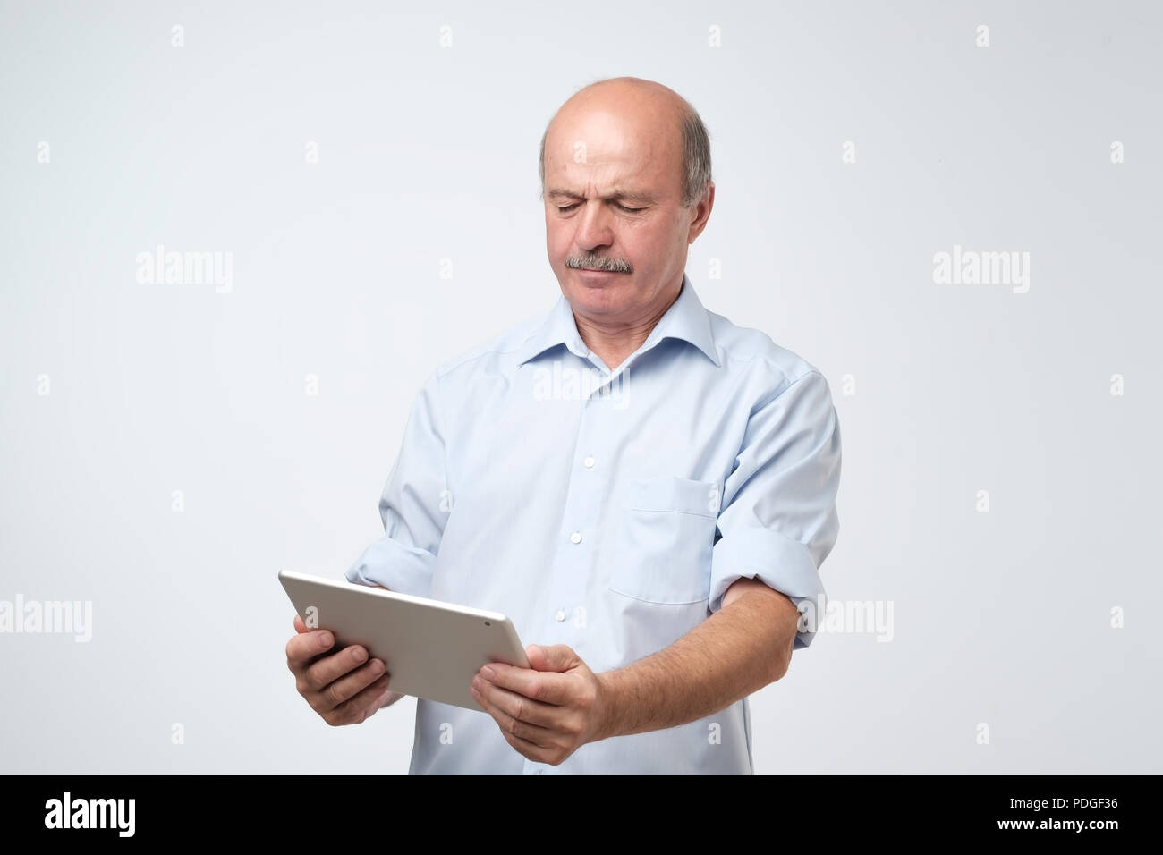 Mature european man using a digital tablet. He is puzzled and confused ...