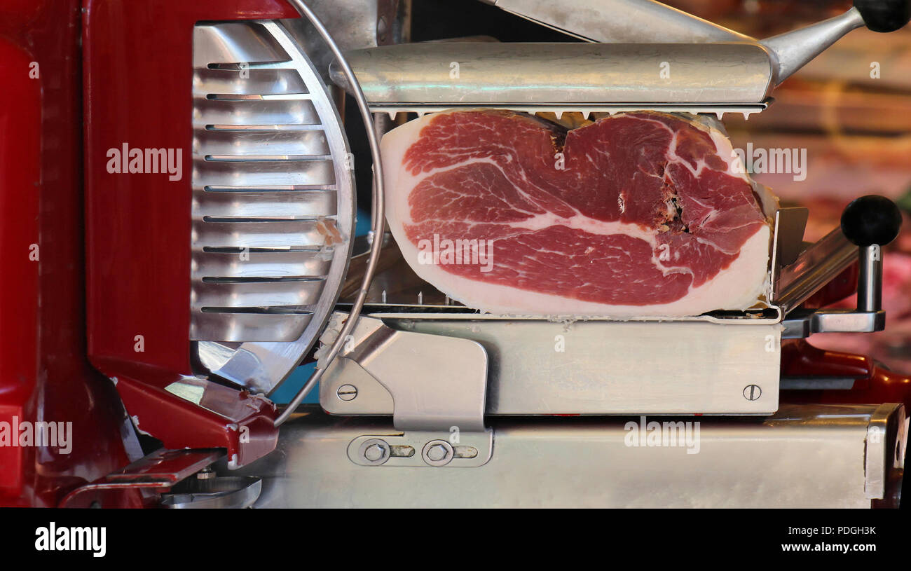 Italian prosciutto inside slicer machine sold on market Stock Photo - Alamy