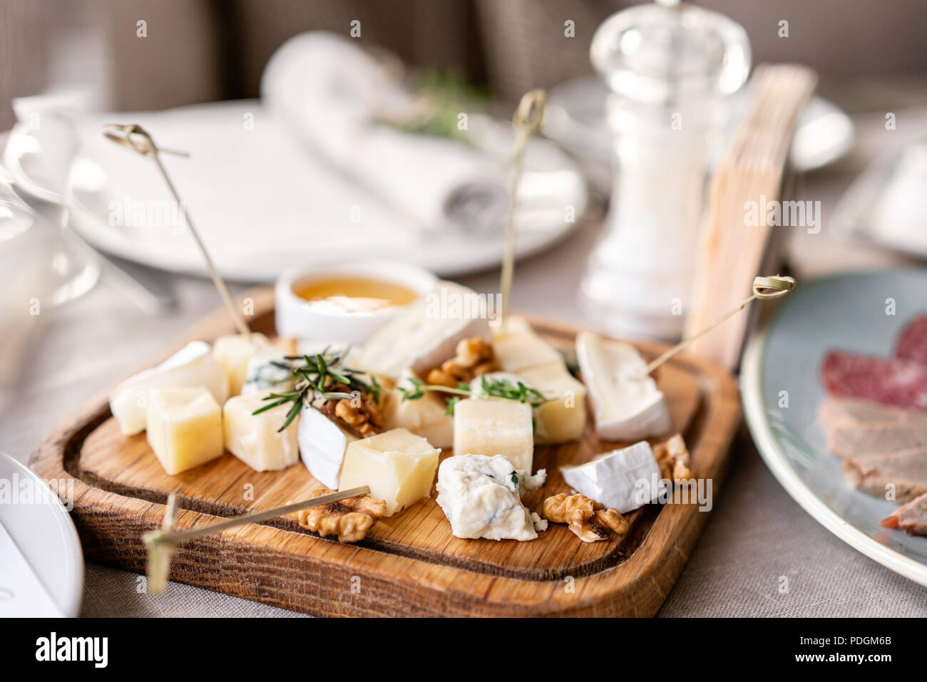 Cheese plate. Delicious cheese mix with walnuts, honey on wooden table ...