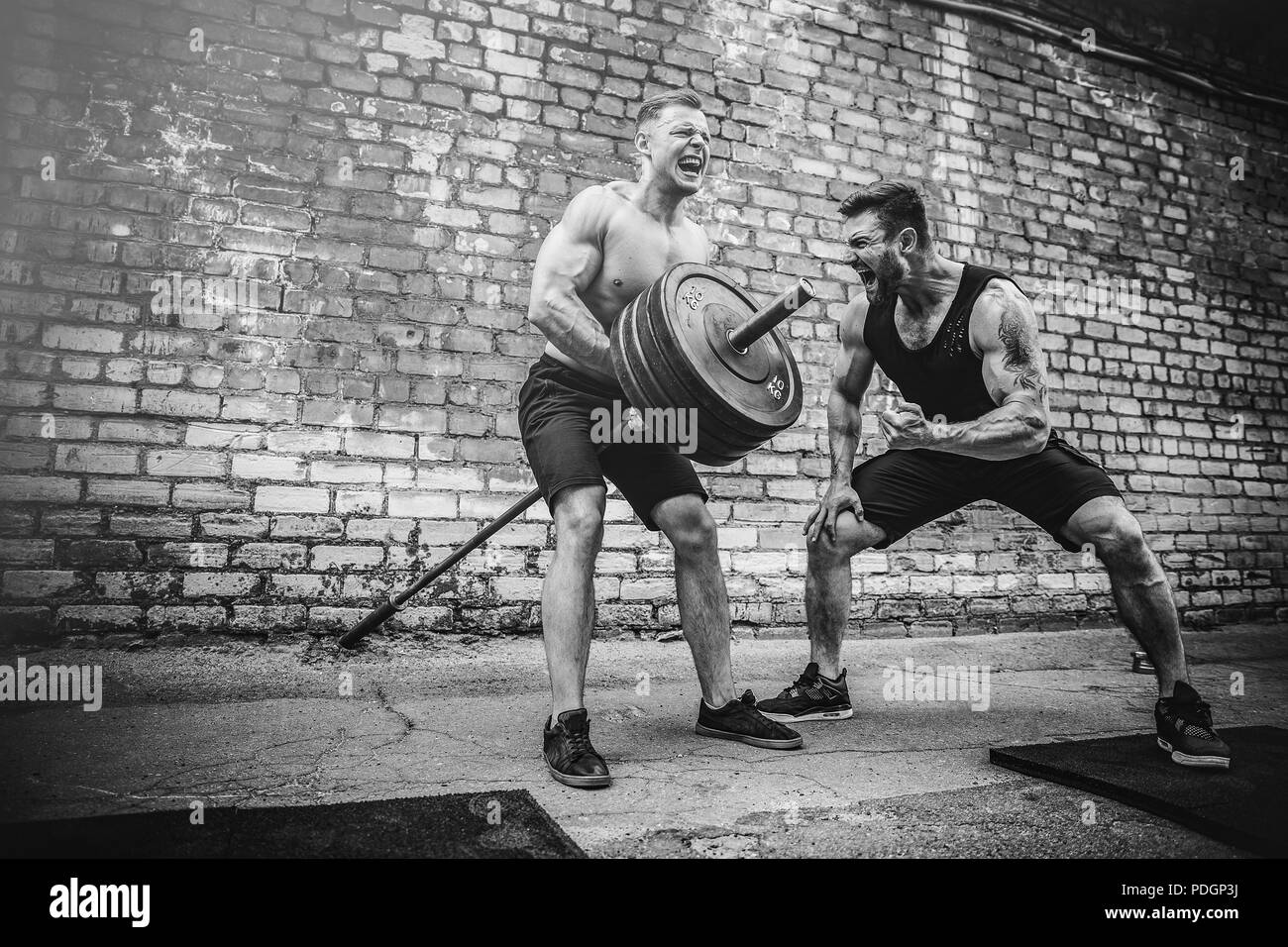 Two muscular athletes training, one raise the bar when other is ...