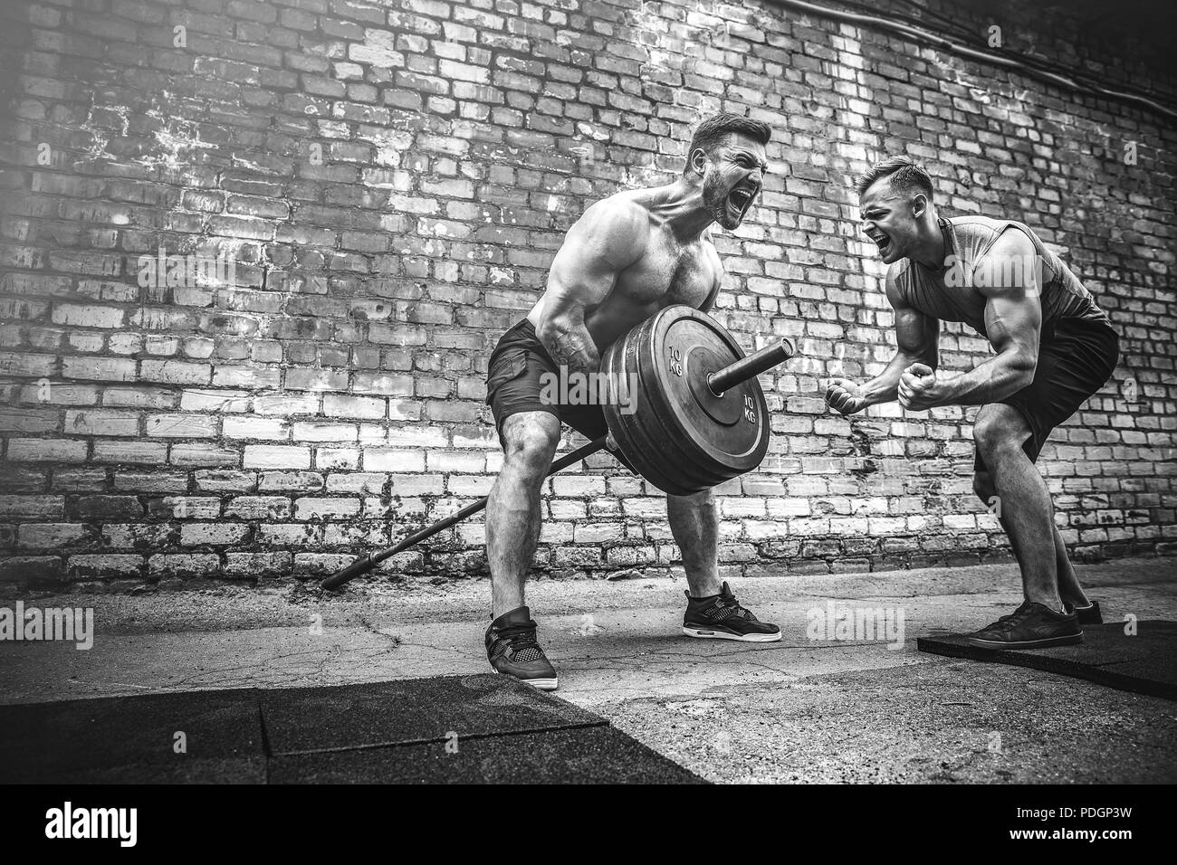 Two muscular athletes training, one raise the bar when other is ...