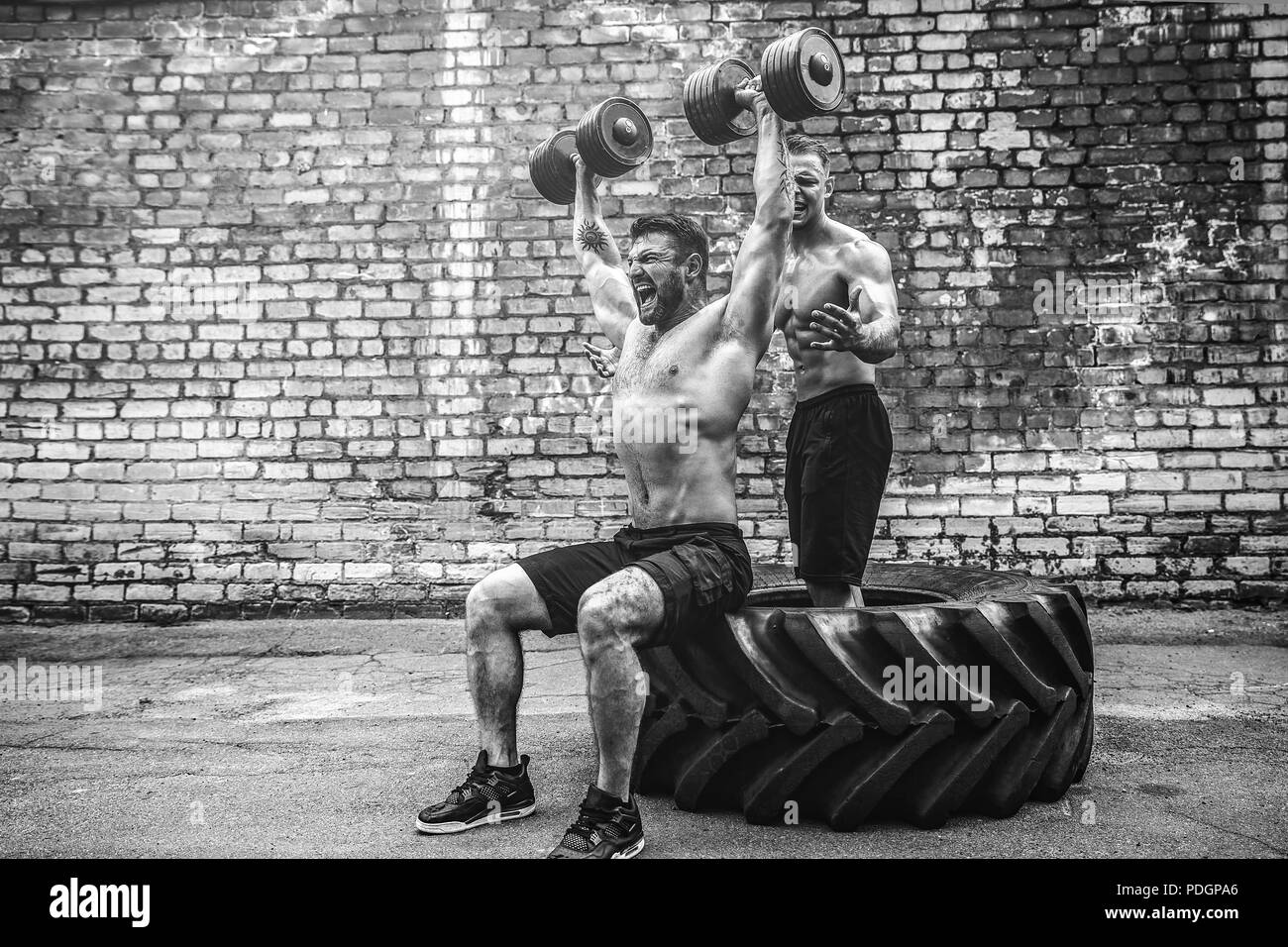 Two muscular athletes training, one raise, push the barbbell when other ...