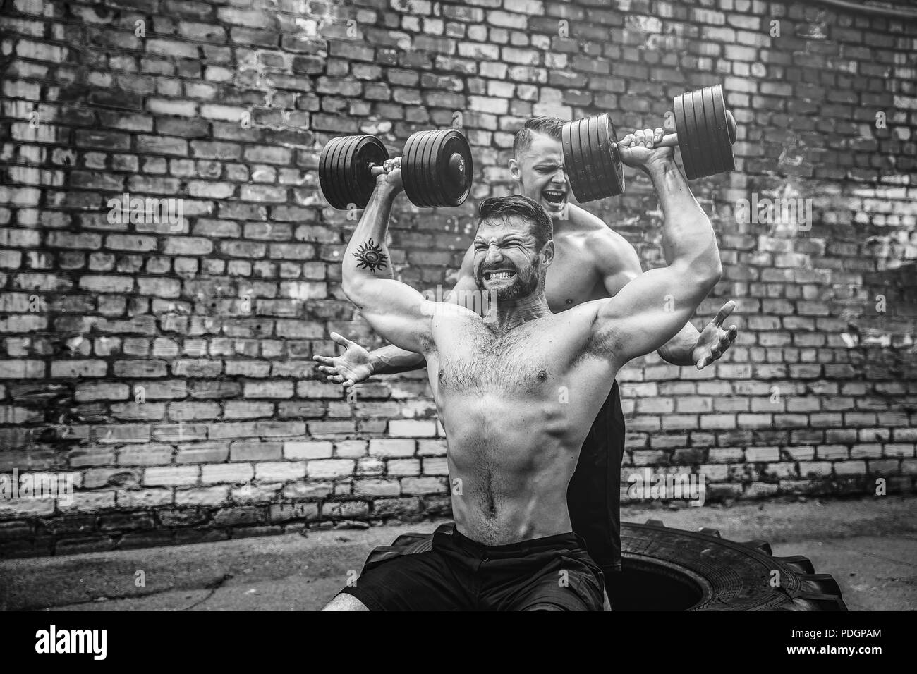 Two muscular athletes training, one raise, push the barbbell when other ...