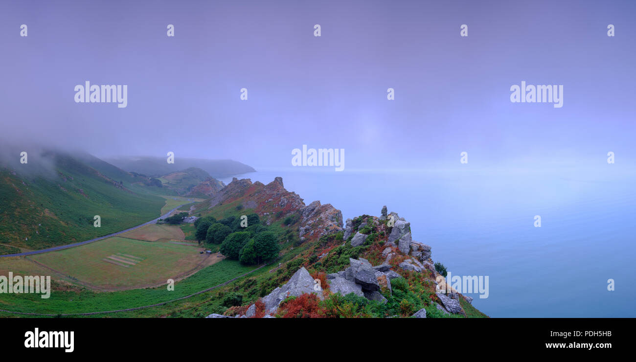 Summer sunrise with a clearing sea mist over the Valley of Rocks, near ...