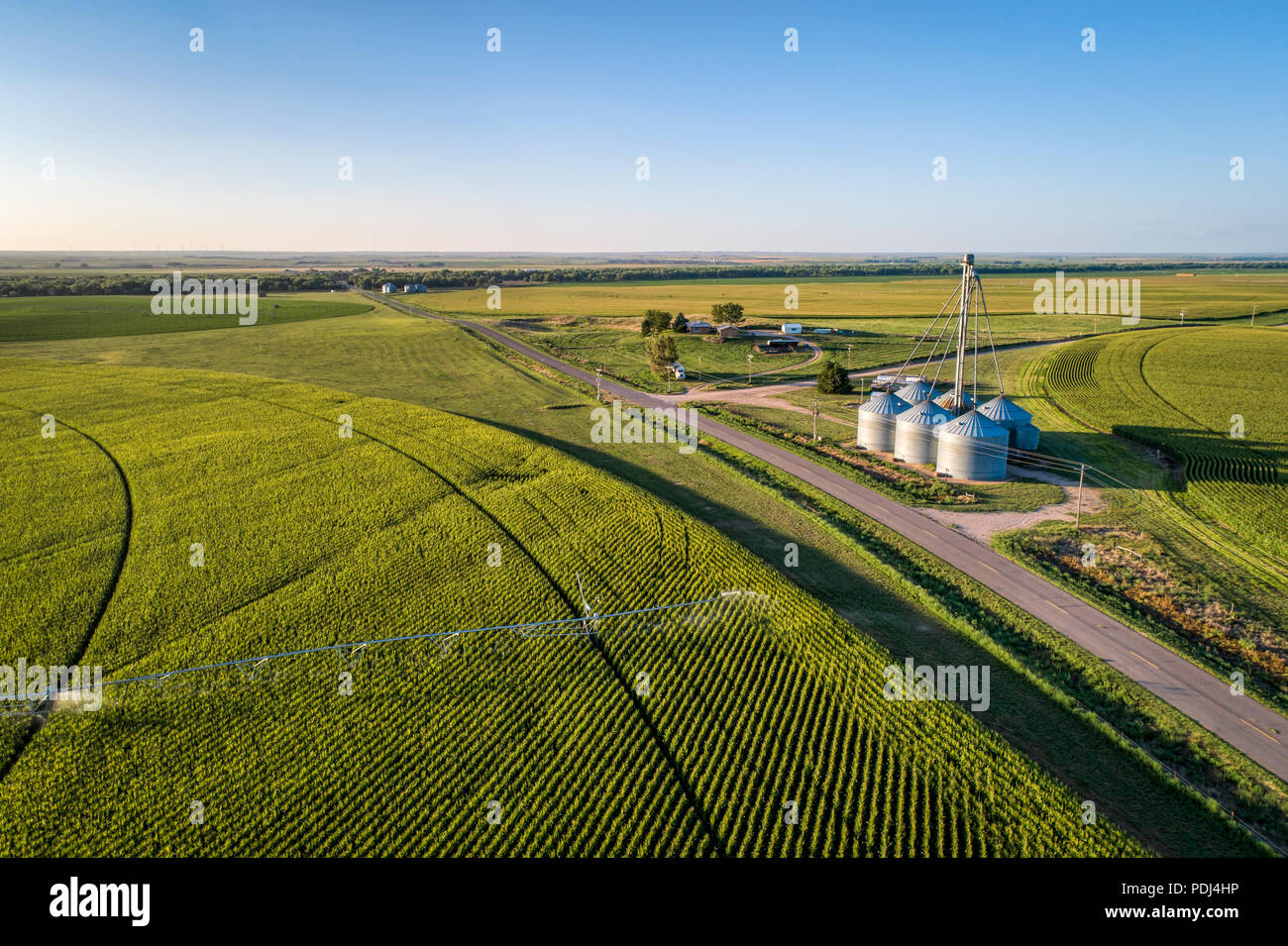 aerial view of corn field with sprinkler, silo, and farm buildings in ...