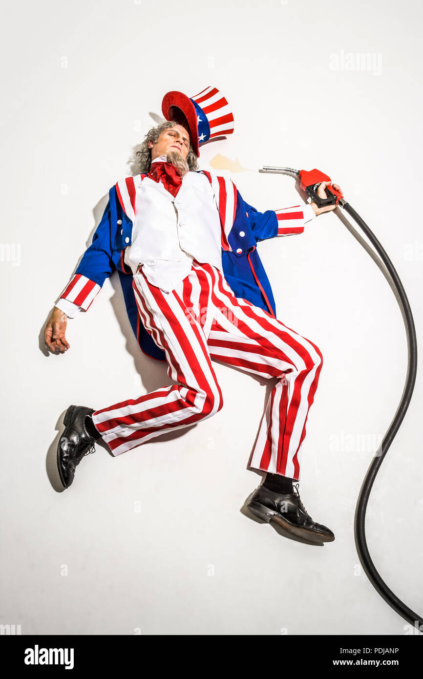 Uncle Sam lying dead next to a gasoline pump nozzle. Addicted to oil / fossil fuels Stock Photo ...