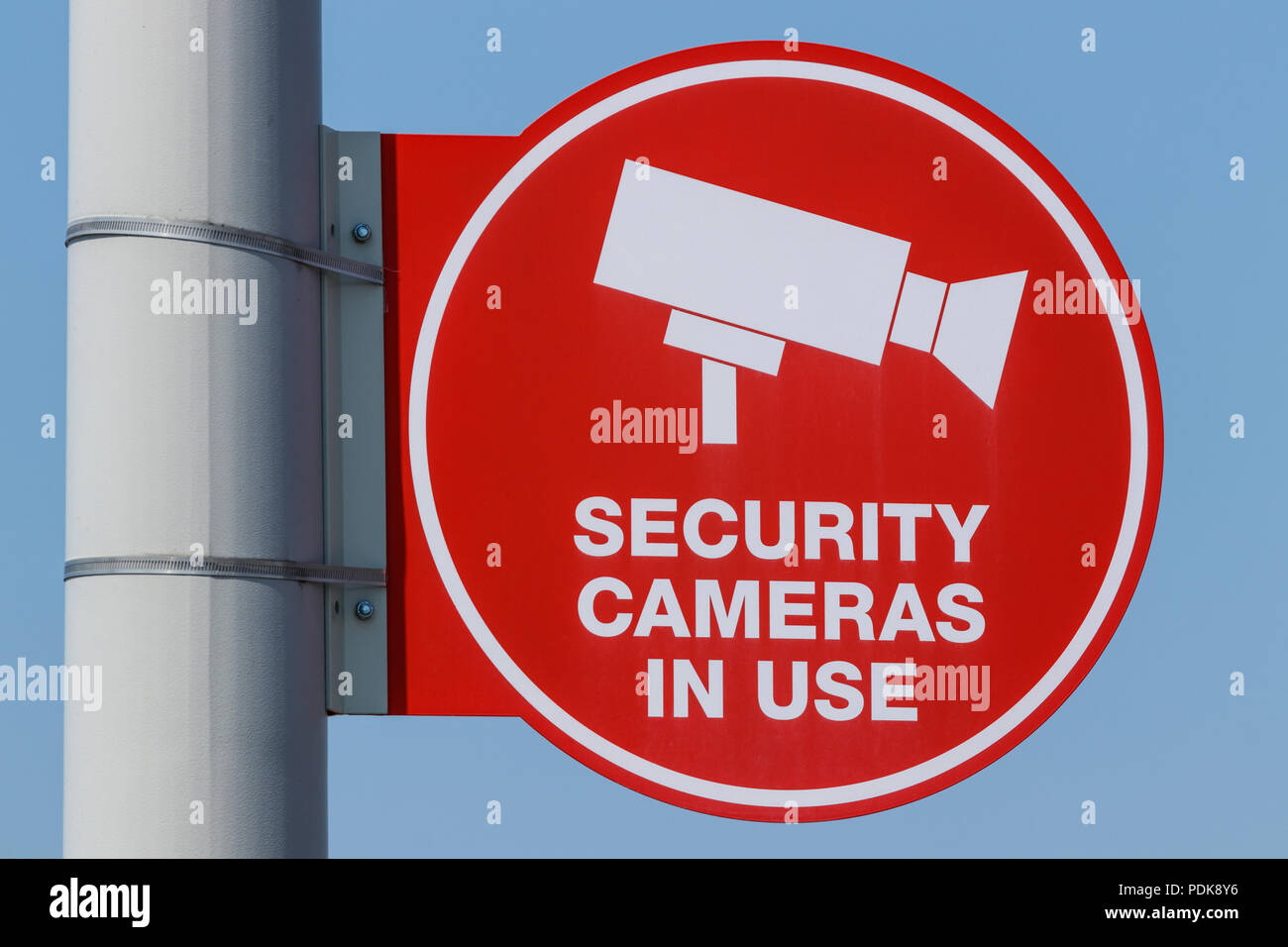 Red Security Camera In Use Sign on Gray Post and Sunny Blue Sky ...