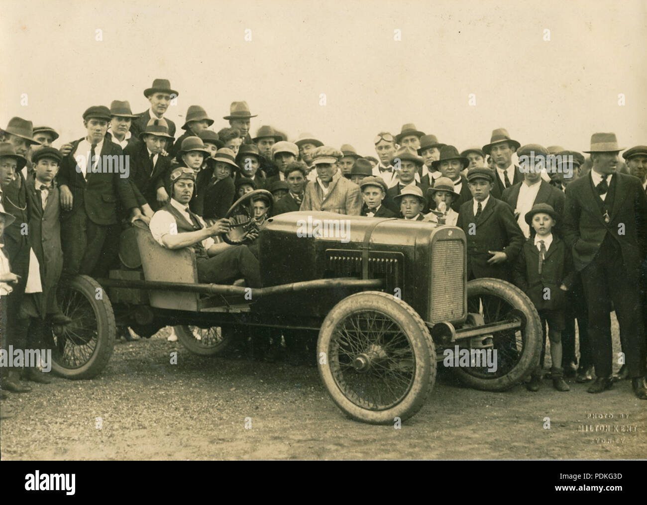 82 Man seated in a modified Overland racing car surrounded by crowd ...