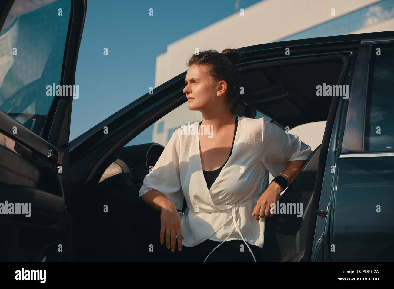 Confident woman getting down from car Stock Photo - Alamy